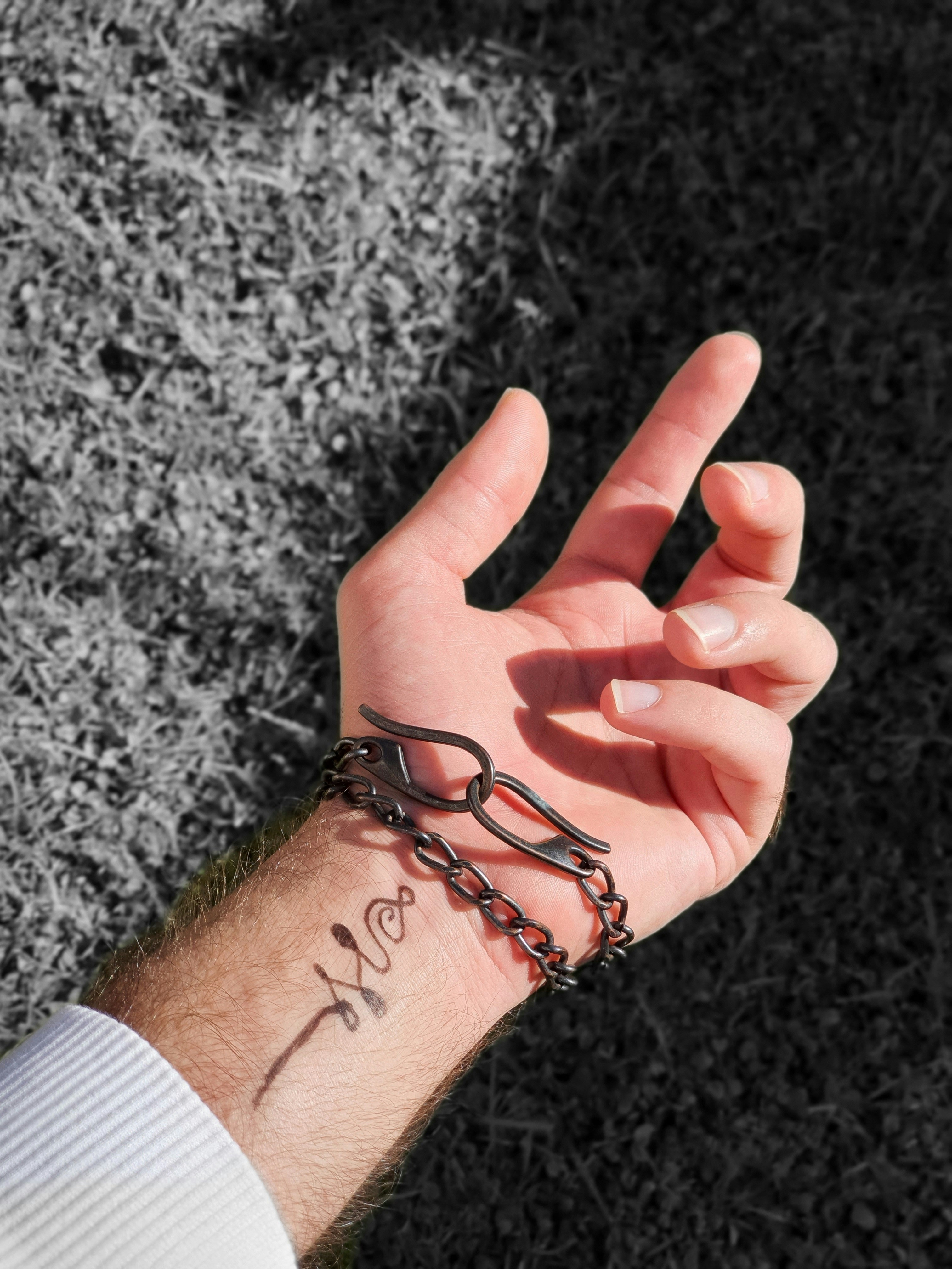 Chains and Script: A Glimpse of Identity on a Weathered Wrist