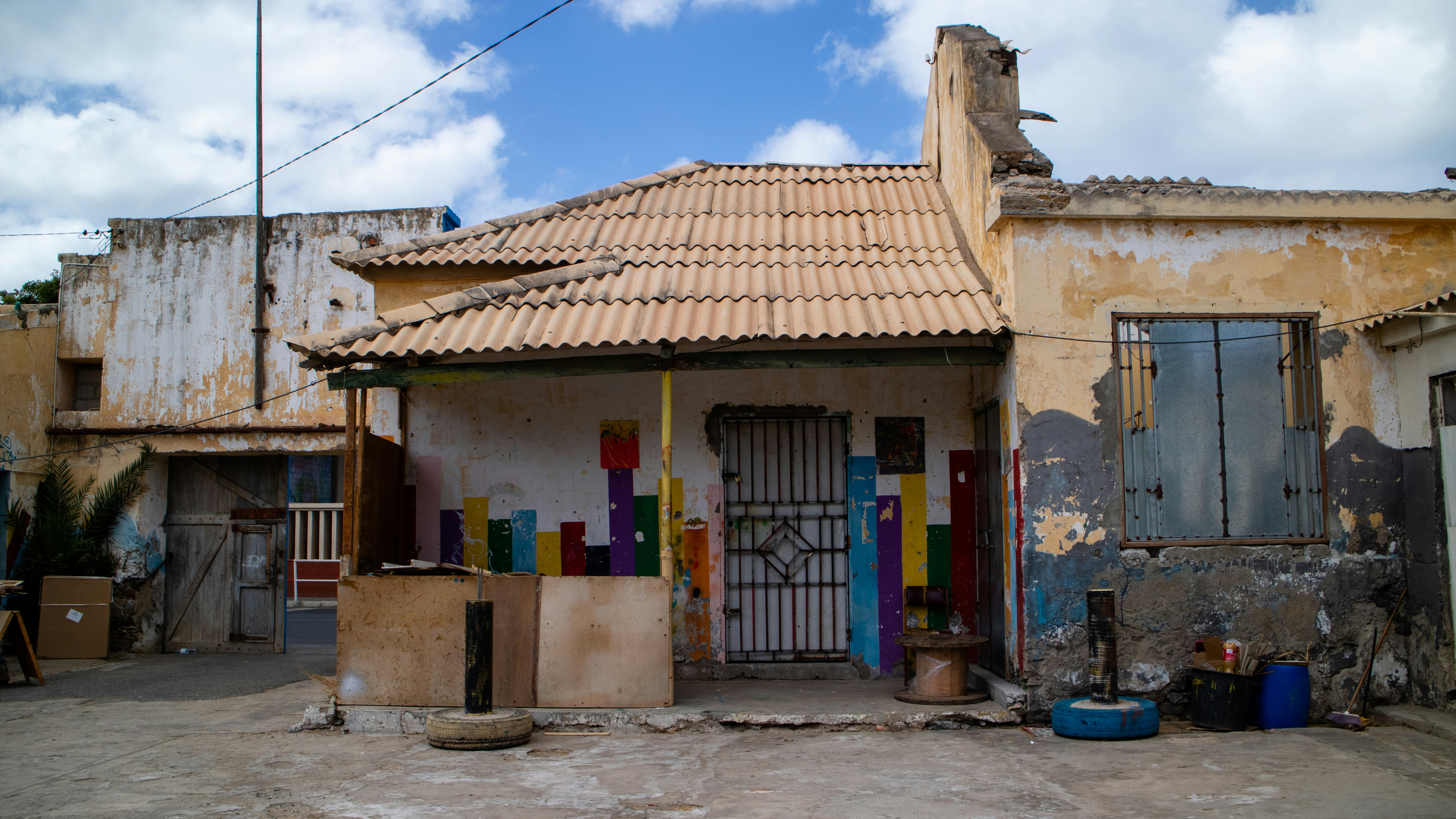 Vibrant, weathered building with colorful pillars and rustic charm, set against a cloudy sky.