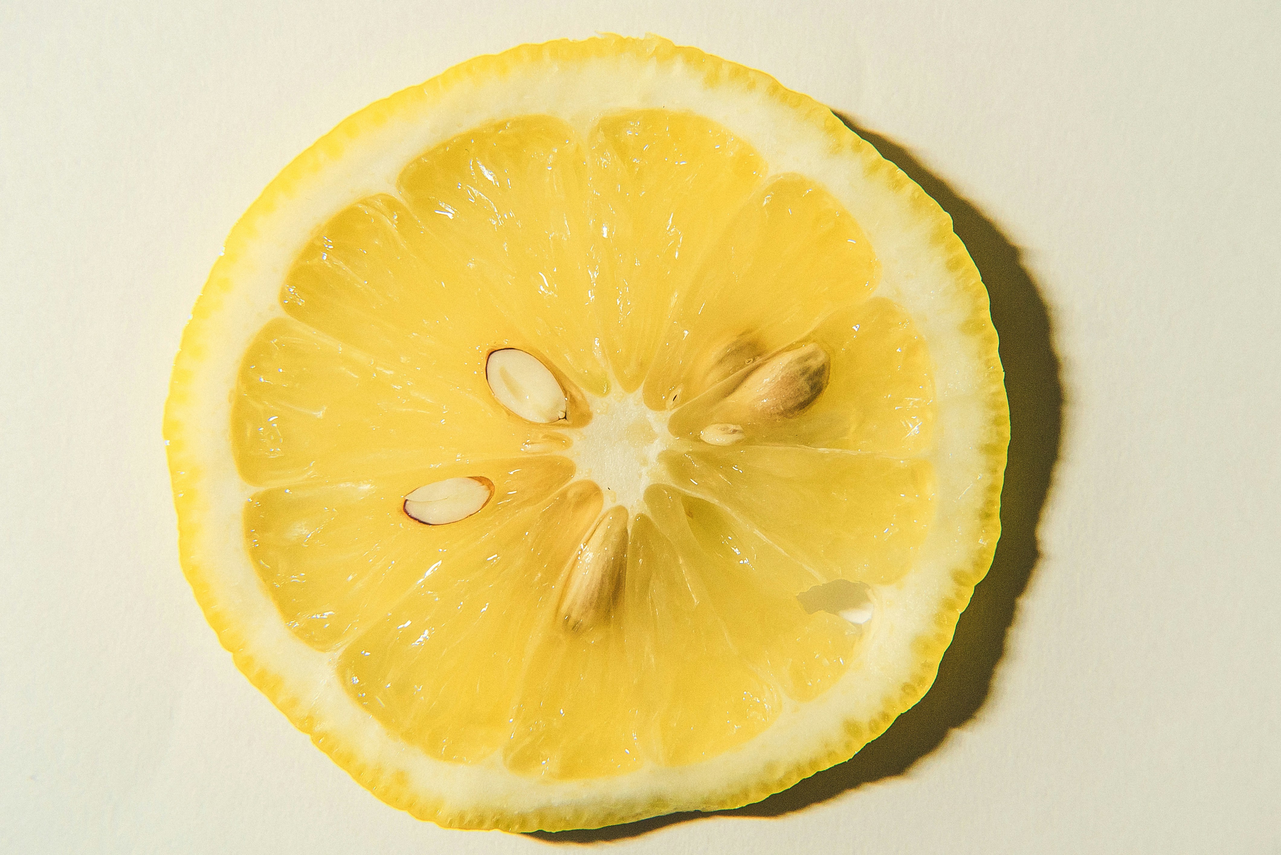 A vibrant lemon slice revealing its juicy interior and seeds against a neutral background.