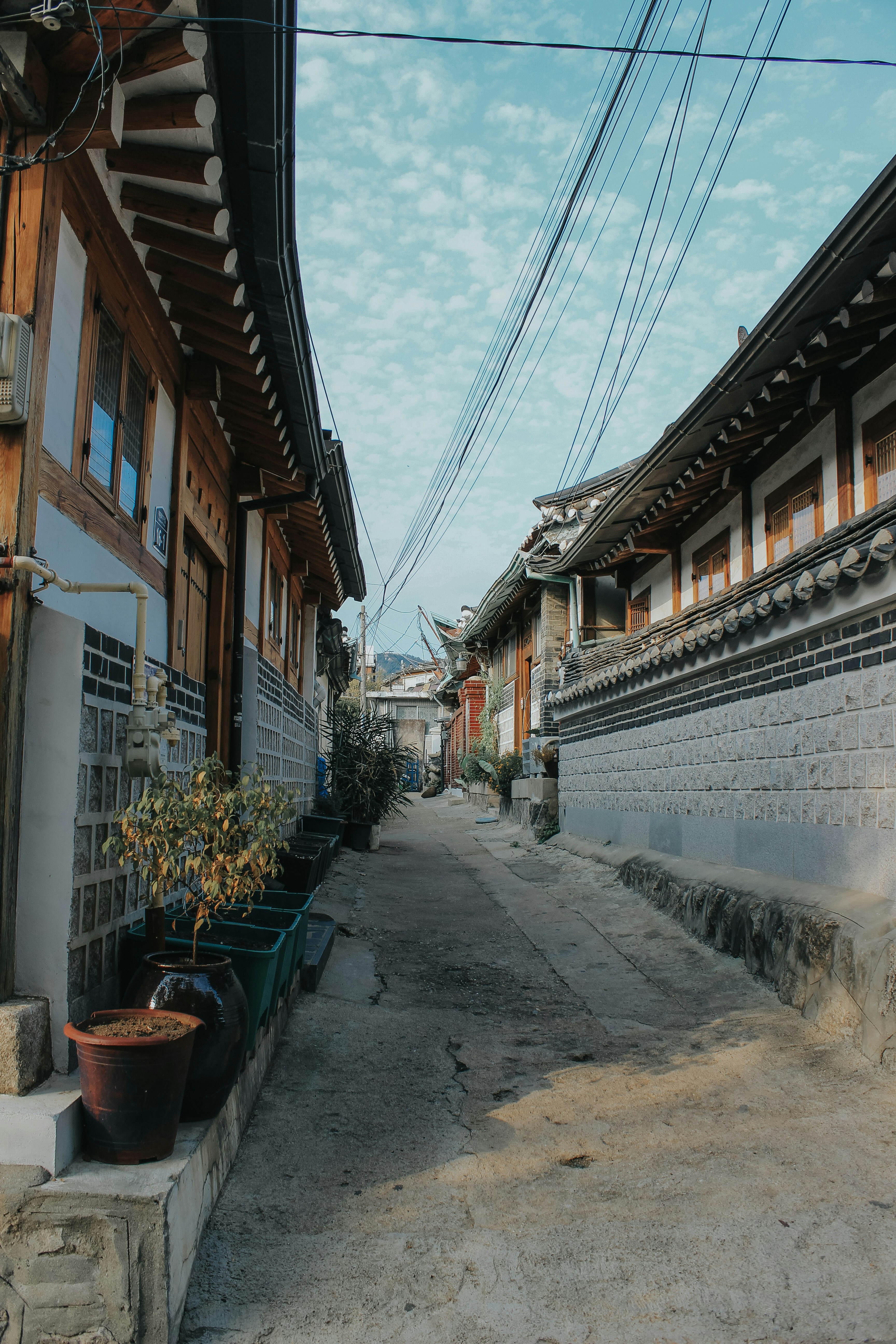 Narrow Alley Between Timbered Rooflines: Sunlit Path to a Distant Door