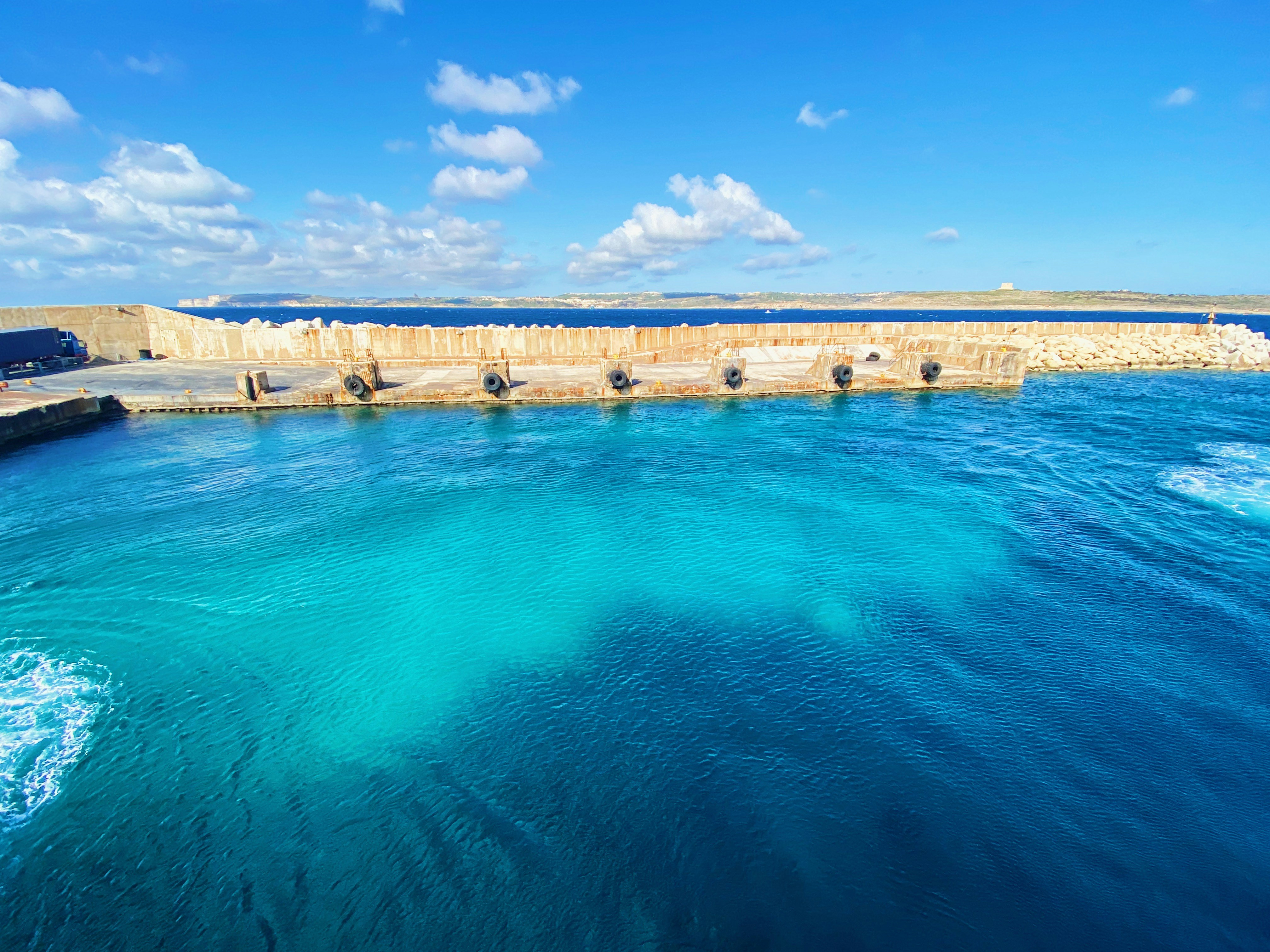 Turquoise Wake Behind a Weathered Breakwater