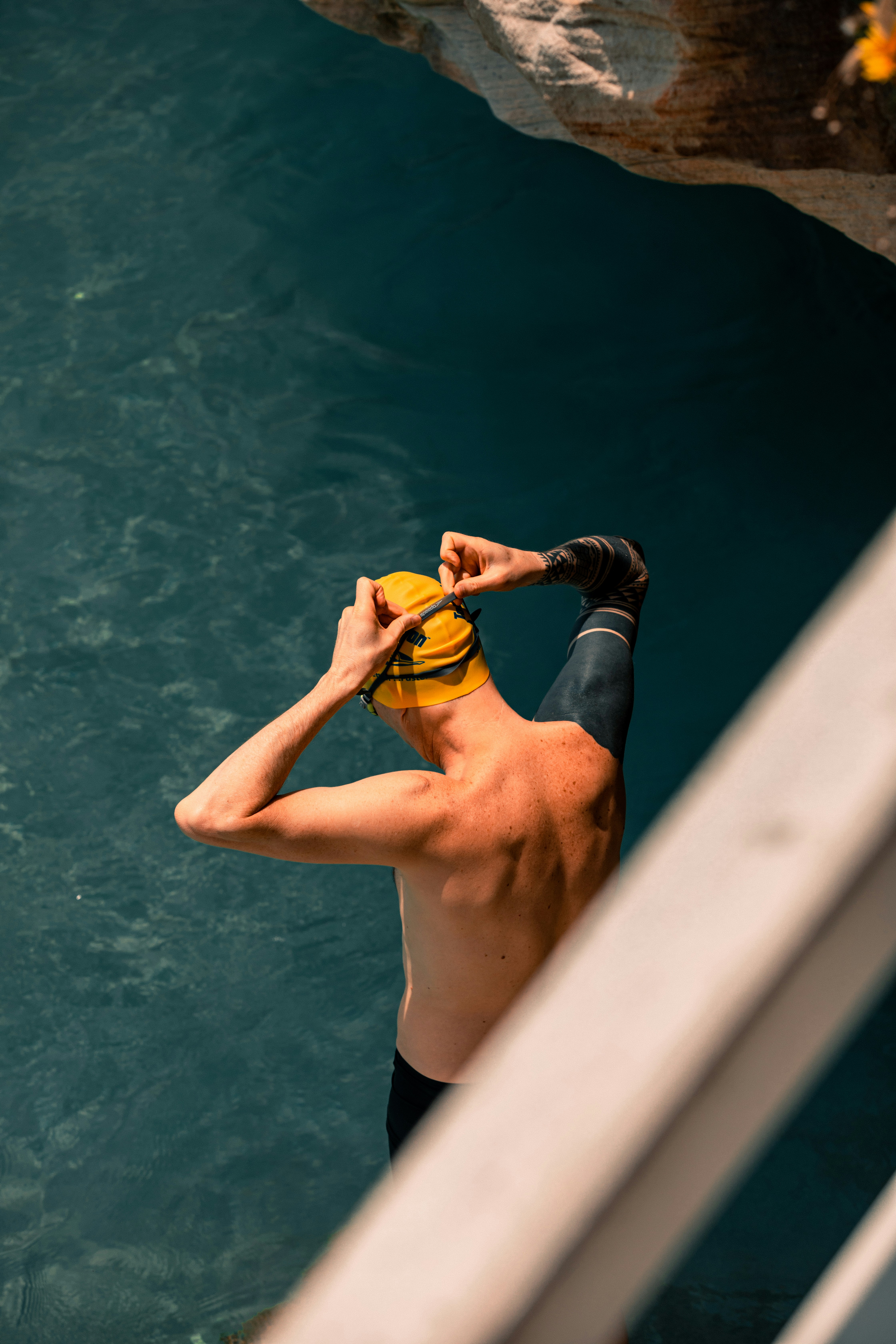 Yellow-Capped Focus: A swimmer tightens goggles at the pool's edge