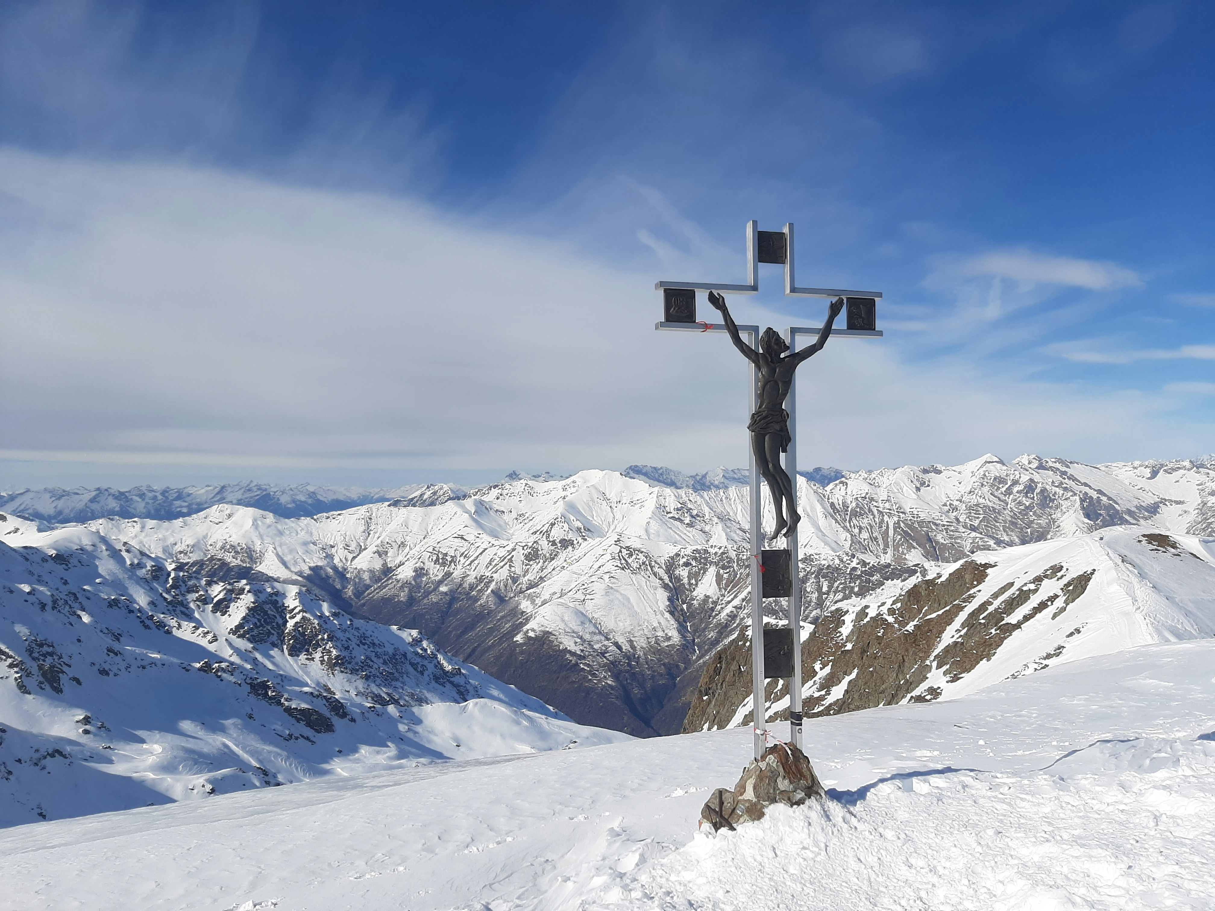 Black wooden cross on snow covered mountain under blue sky during ...