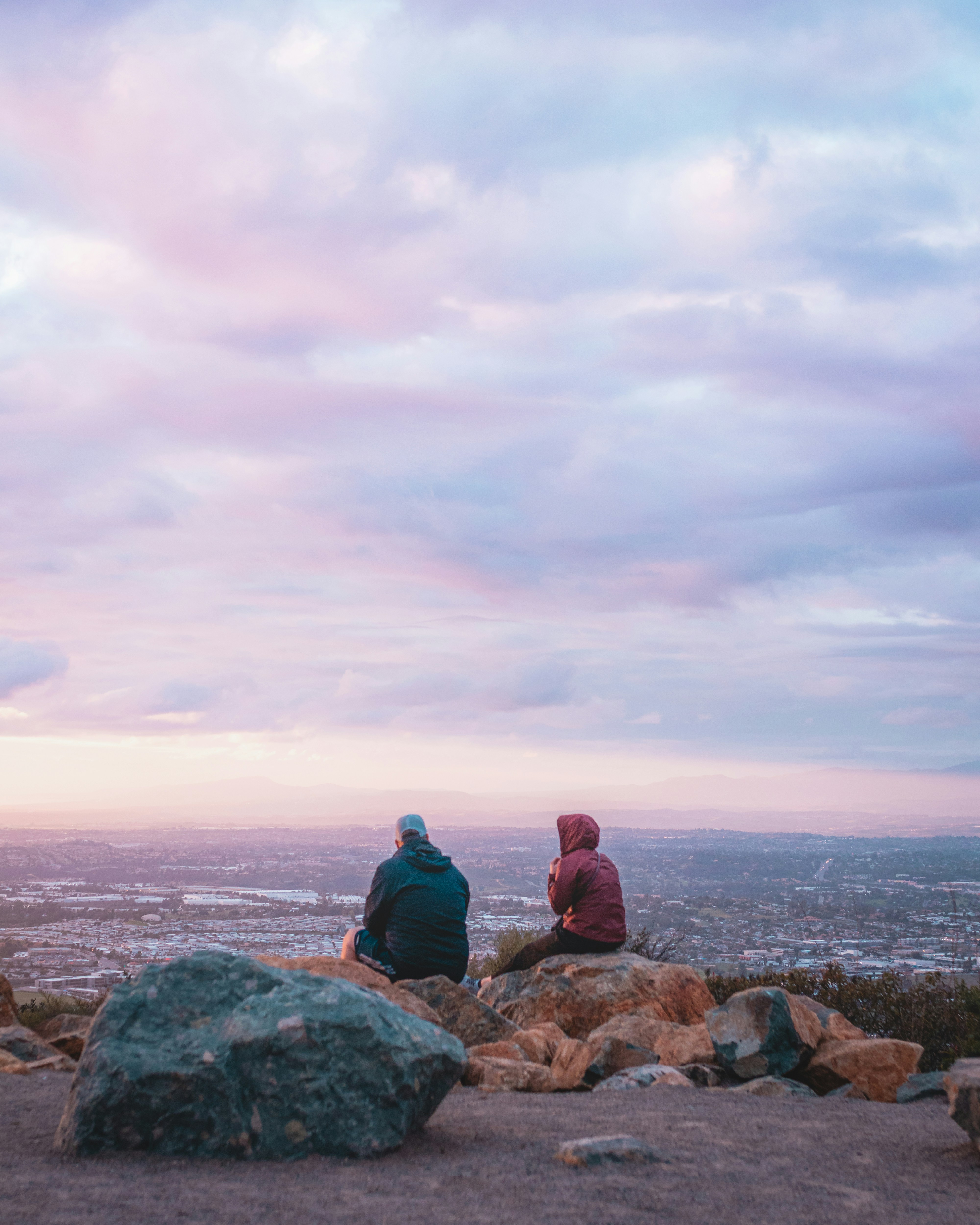 2 person sitting on rock formation near body of water during daytime ...