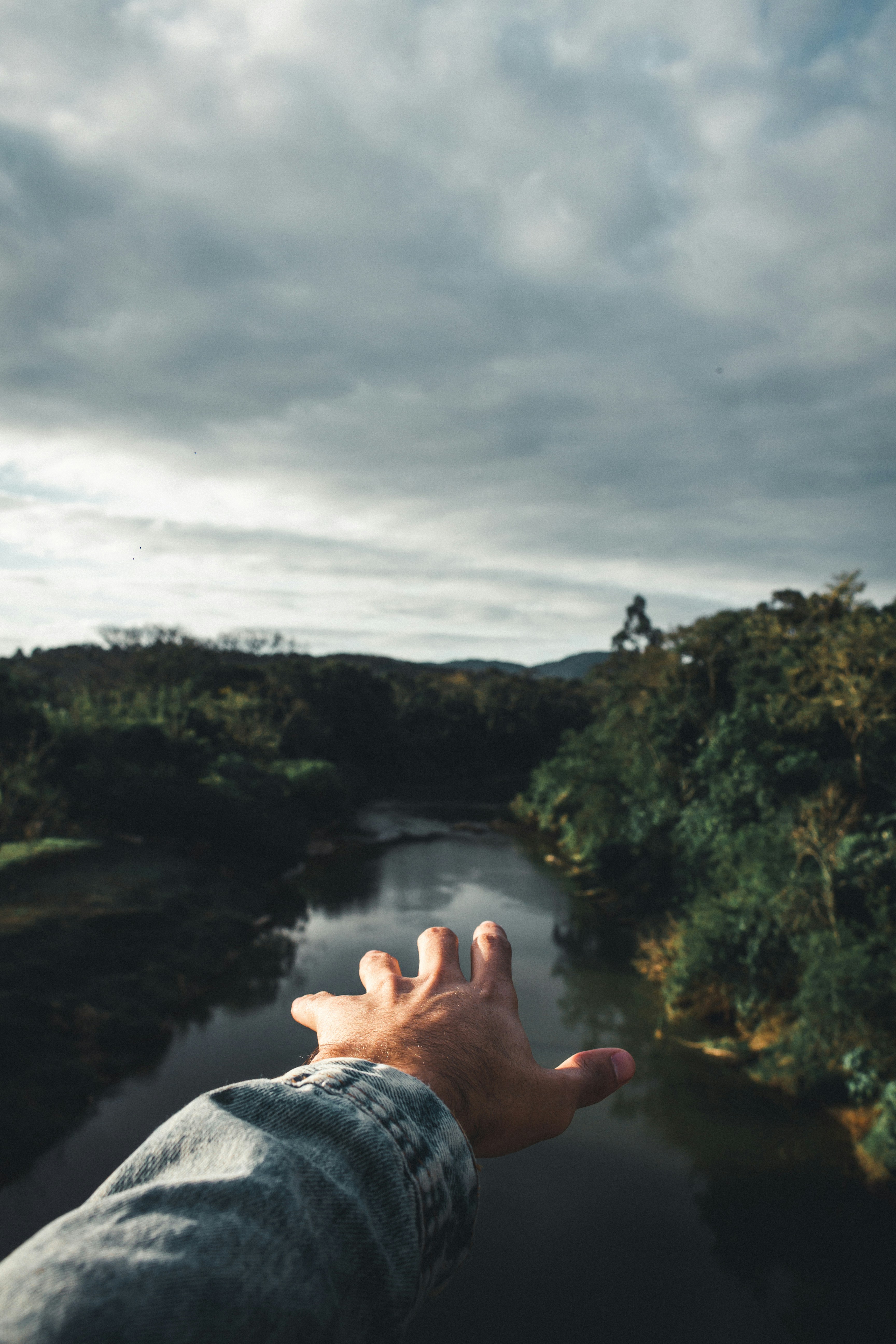 Reach Across the River: A Quiet Gesture Beneath a Brooding Sky