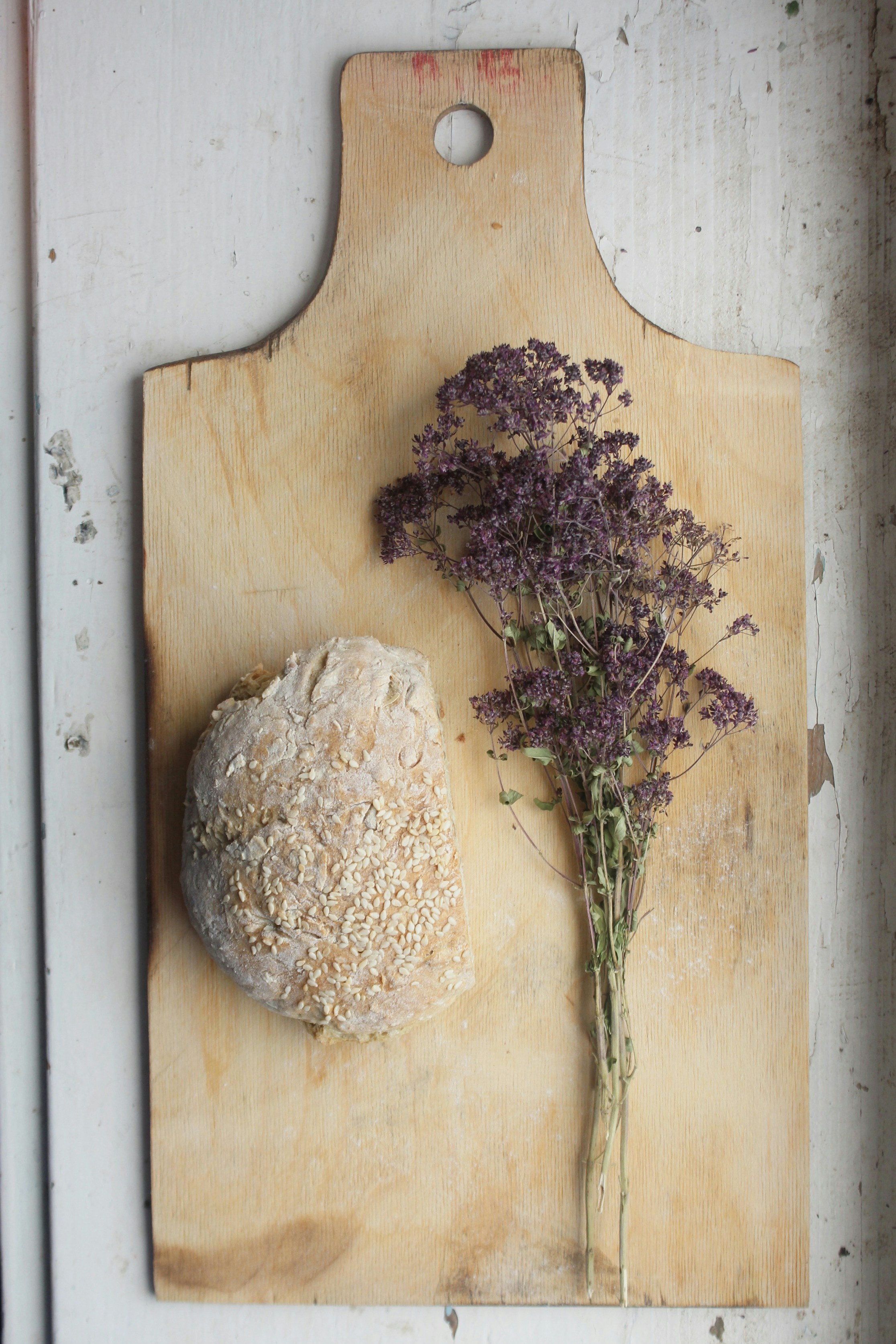 Crust and Bloom: a rustic loaf beside dried purple statice on a weathered cutting board