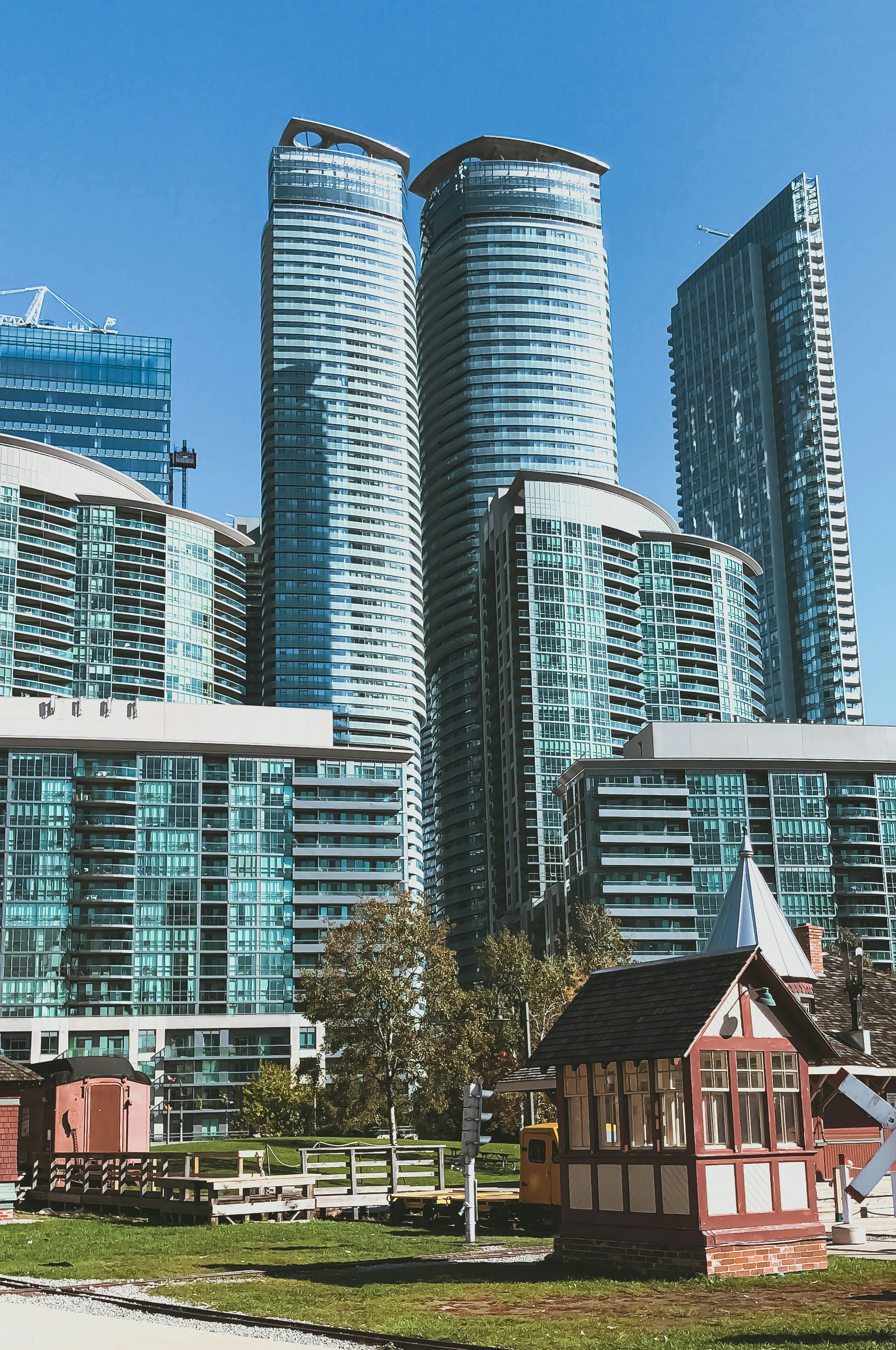 Sleek skyscrapers reflecting sunlight dominate the skyline, juxtaposed with a quaint, historical structure in the foreground.