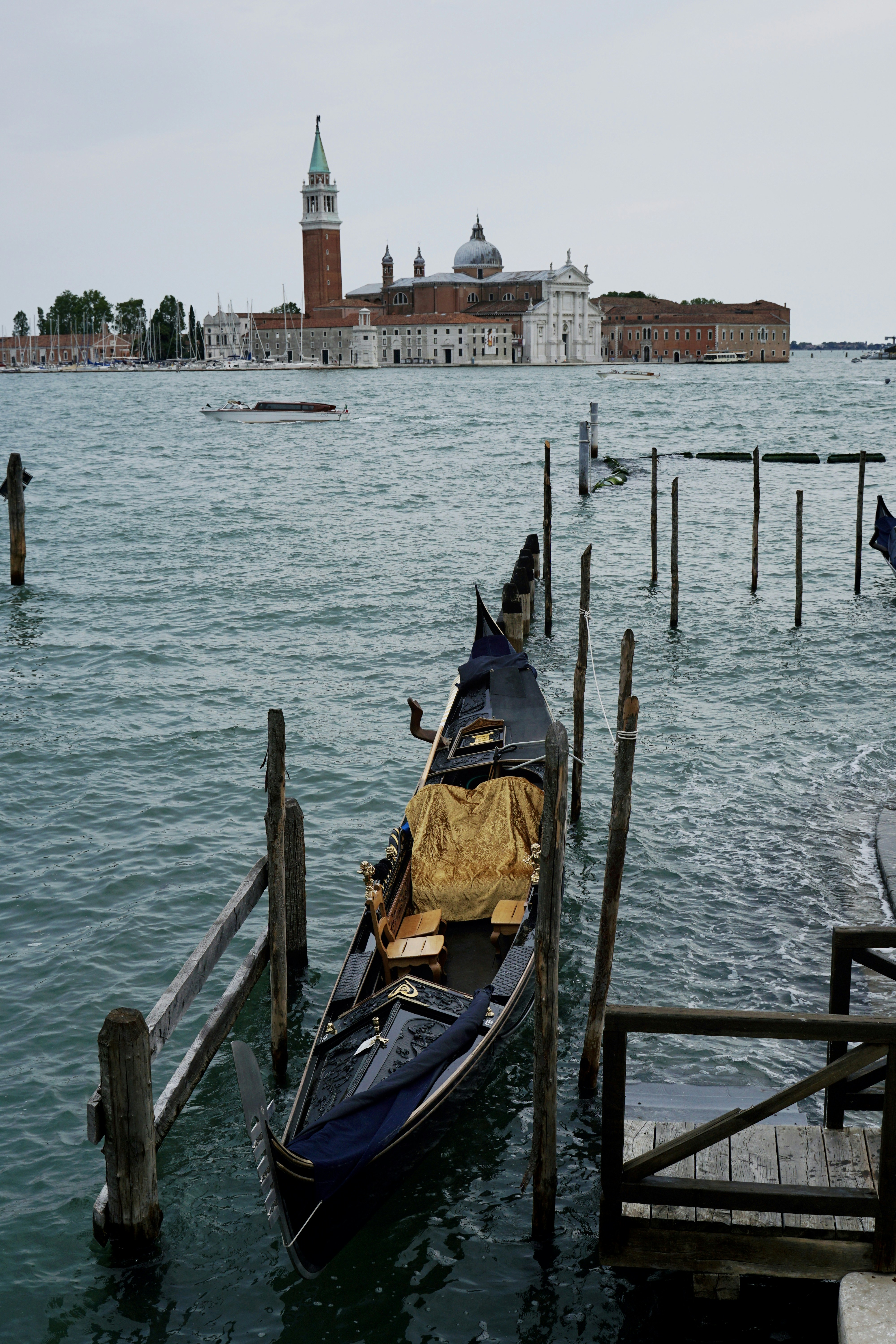 A gondola navigates the tranquil waters of Venice, framed by historic architecture and moored boats in the background.