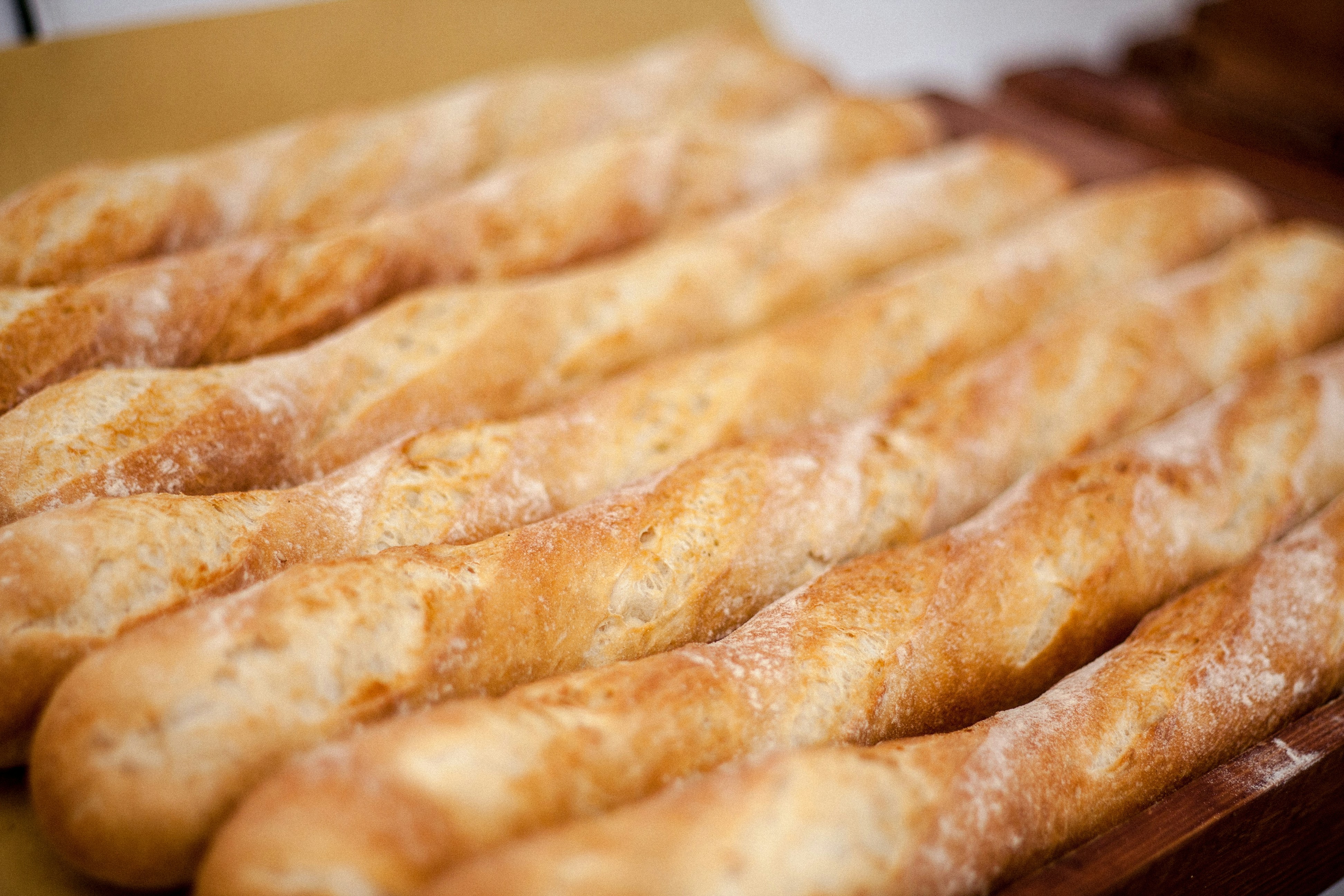 Freshly baked baguettes lined up on a wooden board.