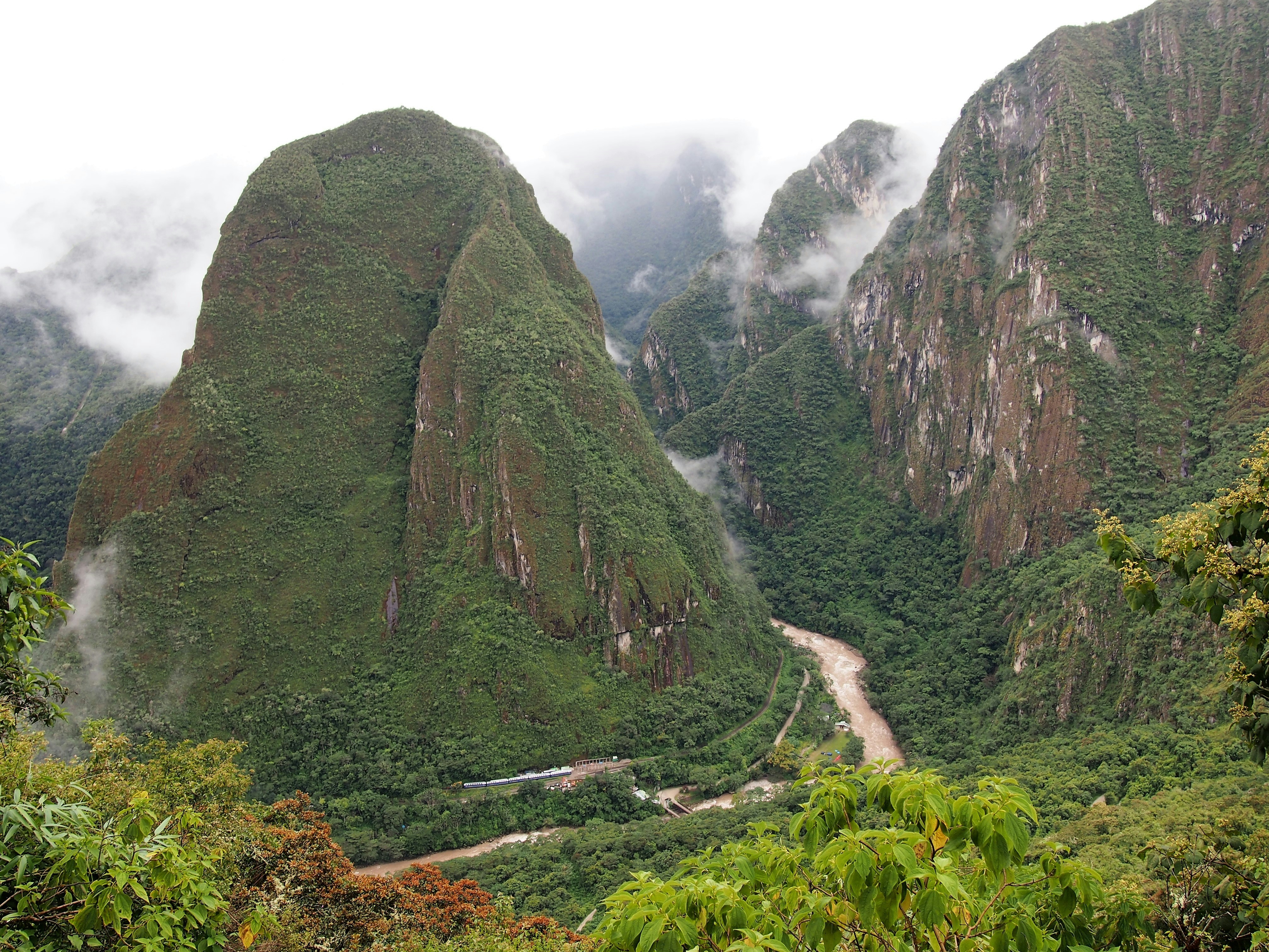 Lush green mountains with mist and clouds in a deep valley.