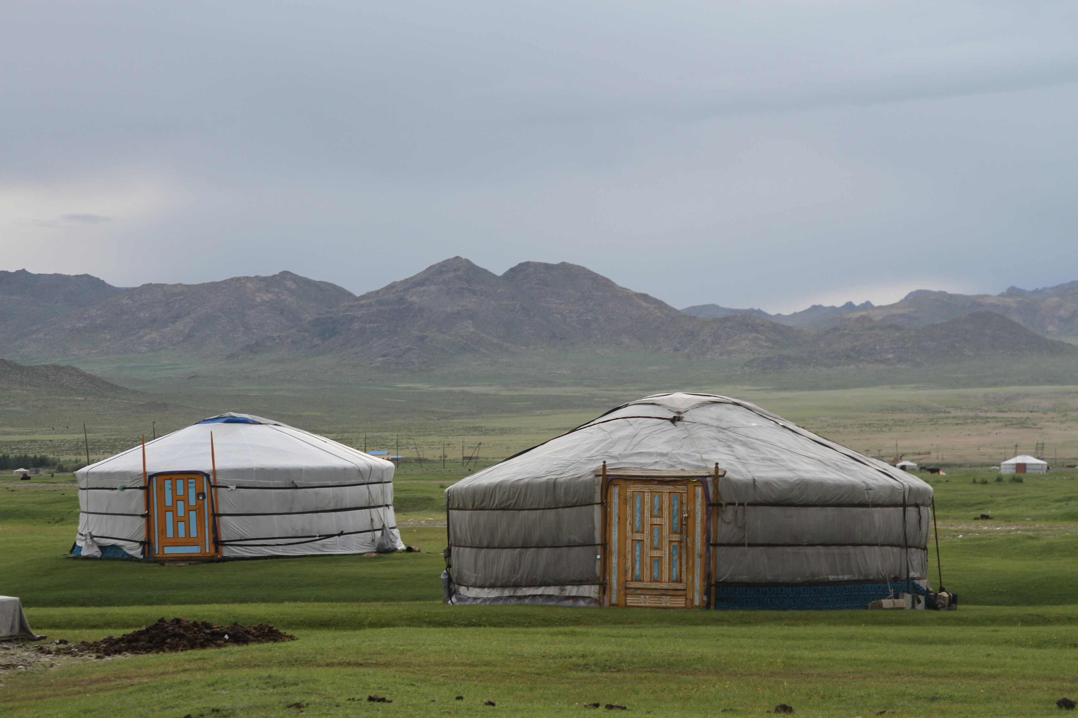 Two traditional yurts set against a vast, mountainous landscape, showcasing the simplicity and beauty of nomadic life. 