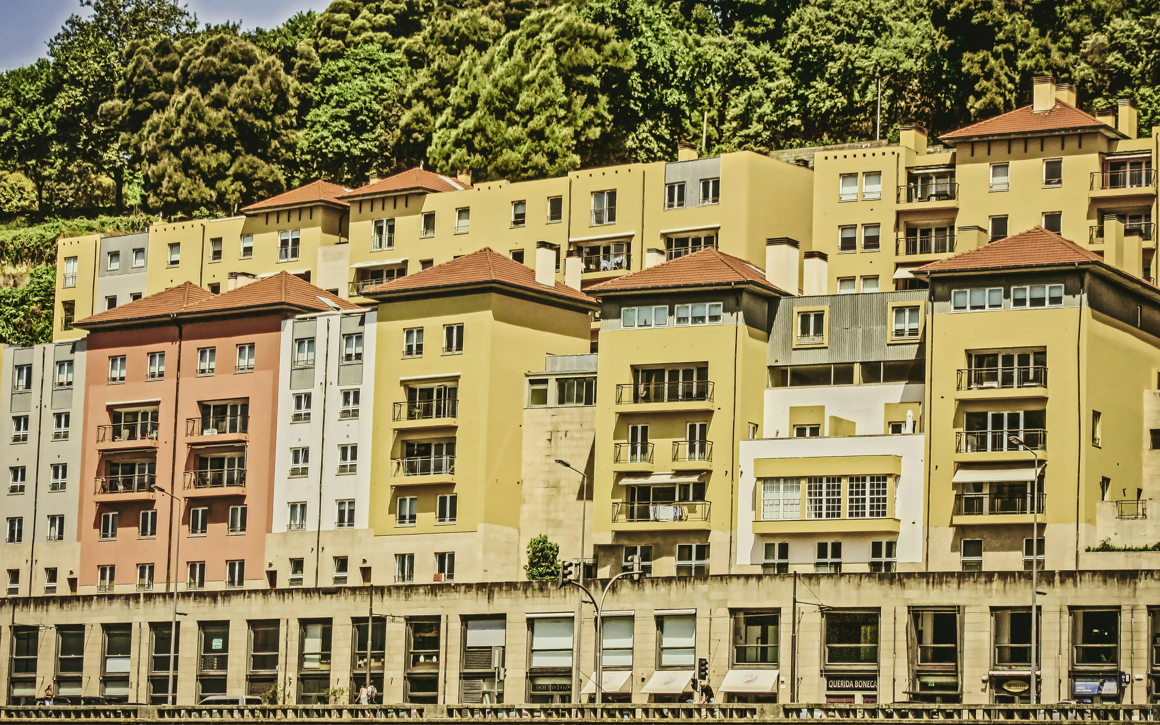 Colorful apartment buildings line the Duoro riverfront under a bright summer sky.
