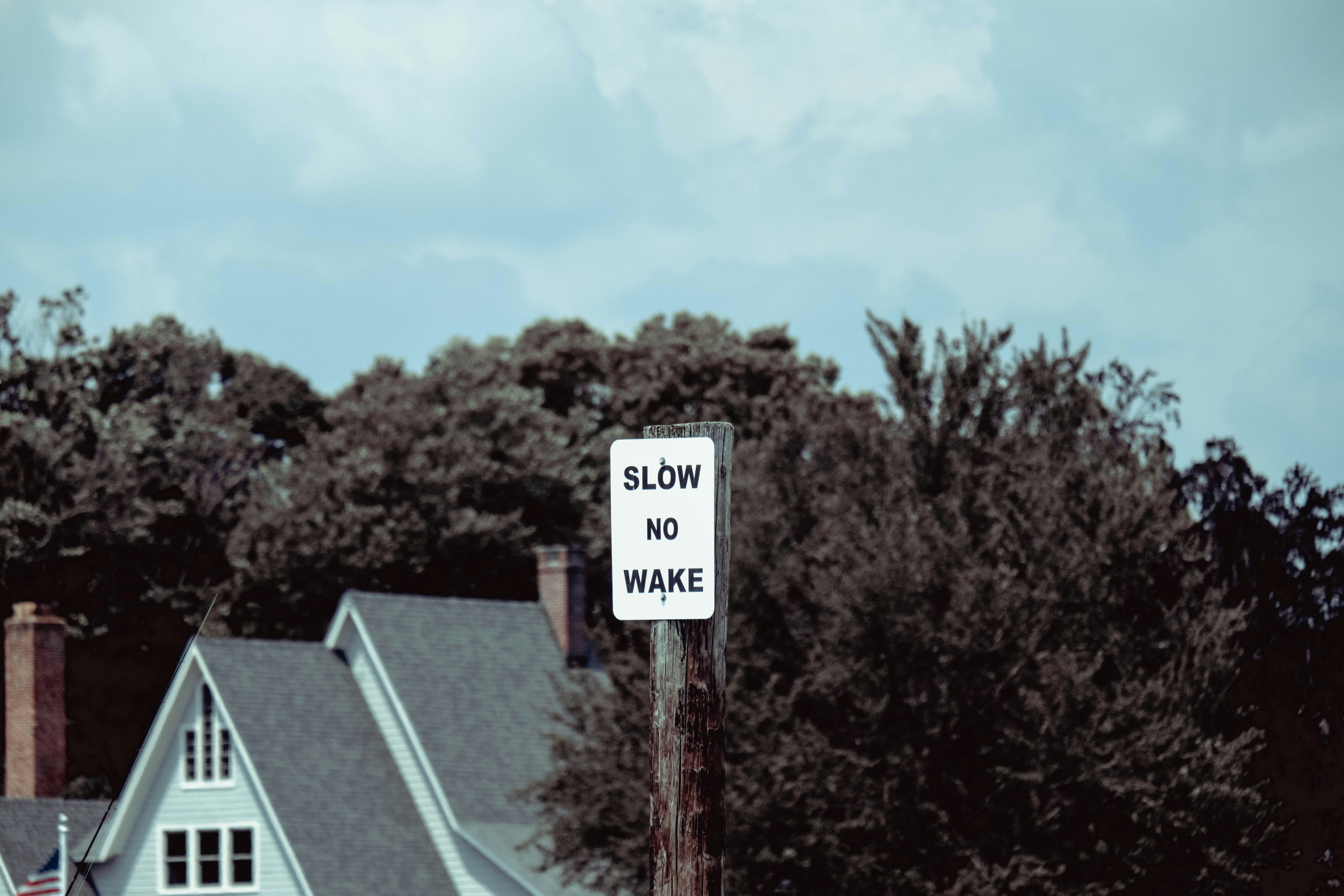 Slow Wake Sign Over a Quiet Suburban Roofline