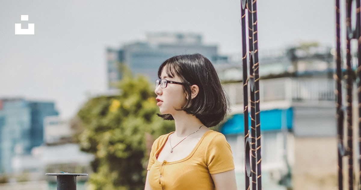 노란 셔츠와 파란 데님 청바지를 입은 여자가 낮에 검은 금속 울타리에 기대어 있다 사진 Unsplash의 무료 의복 이미지