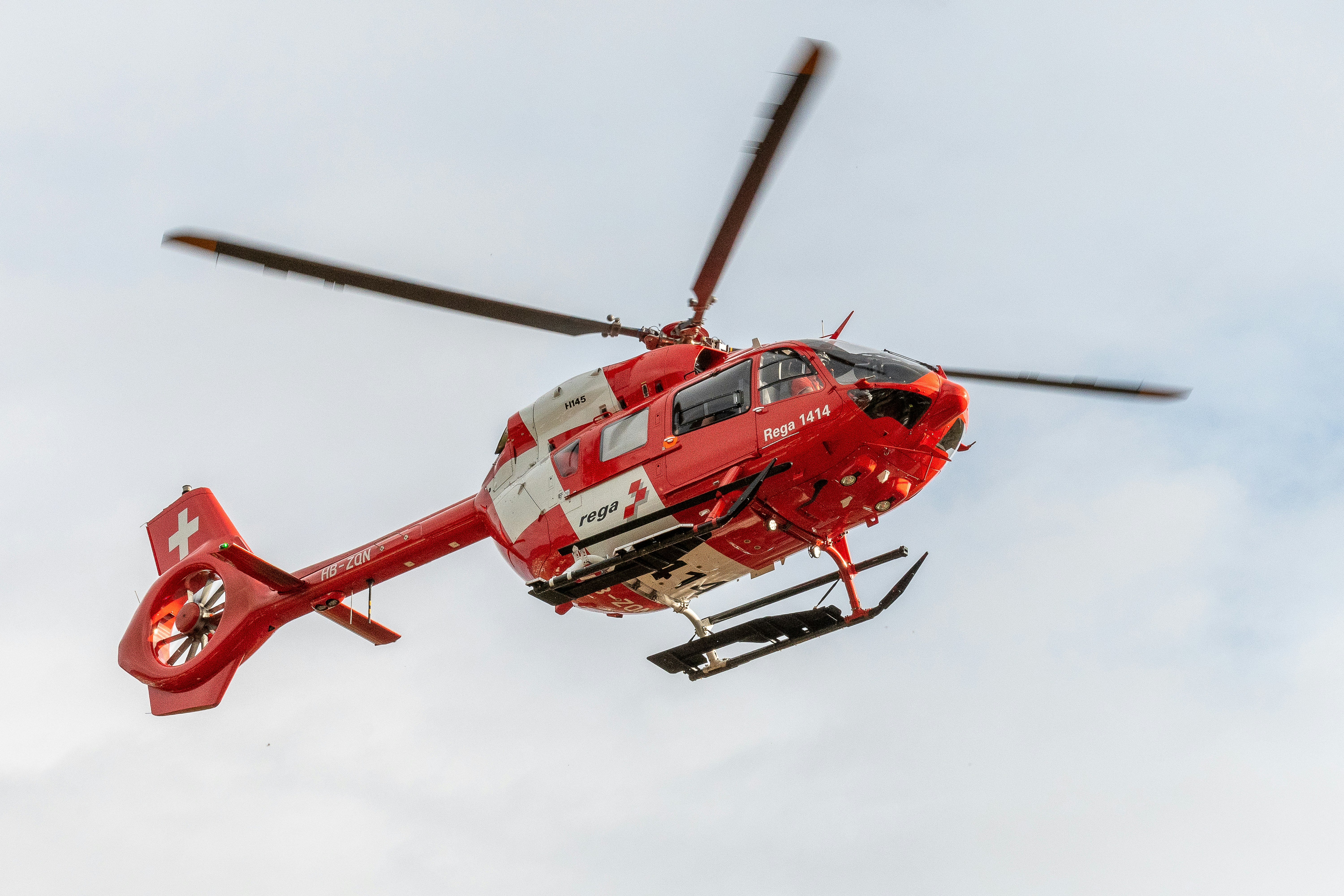 Red Swiss Rescue Helicopter in Flight Against a Soft Sky