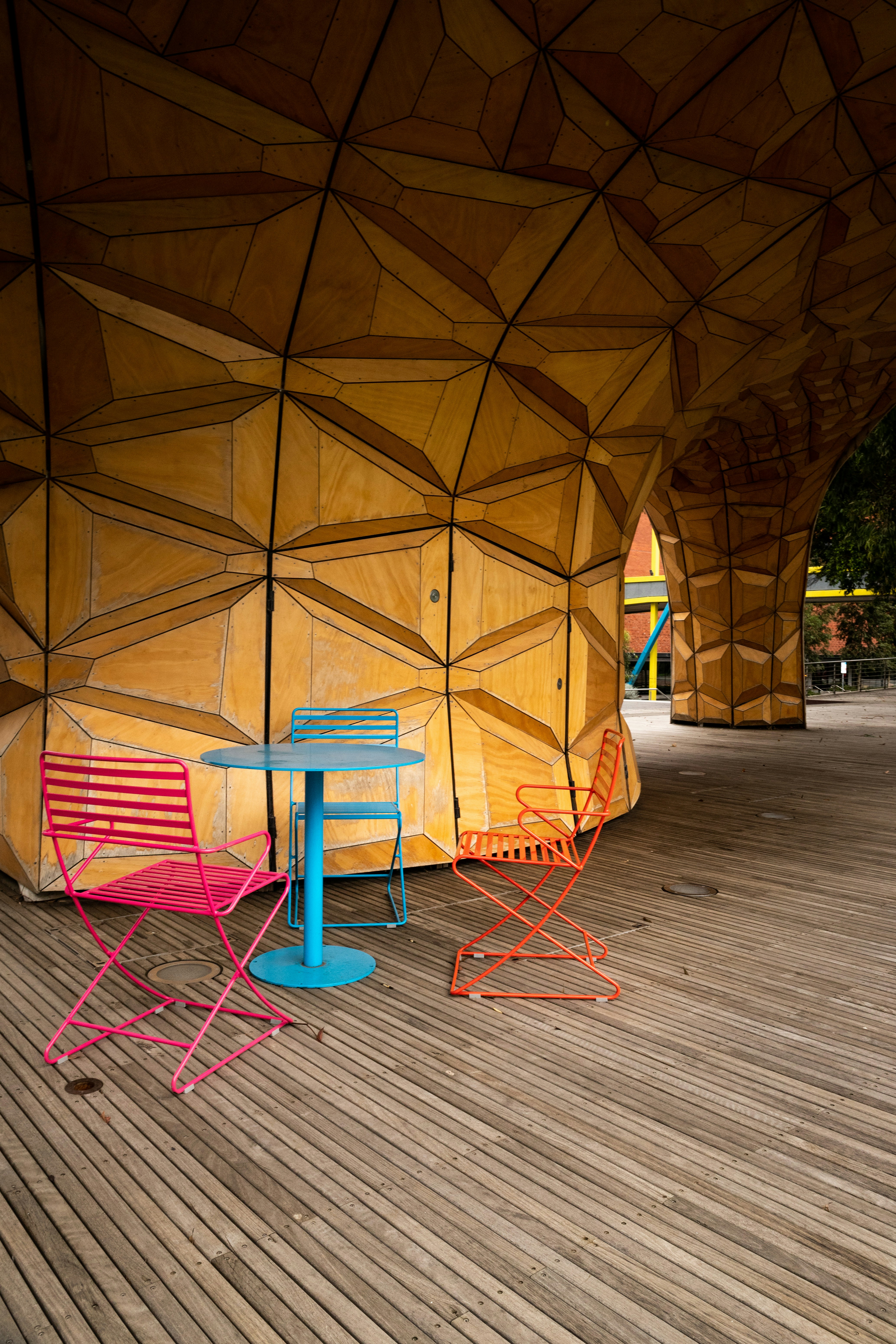 Blue Table Amid a Geometric Timber Pavilion and Colorful Seating