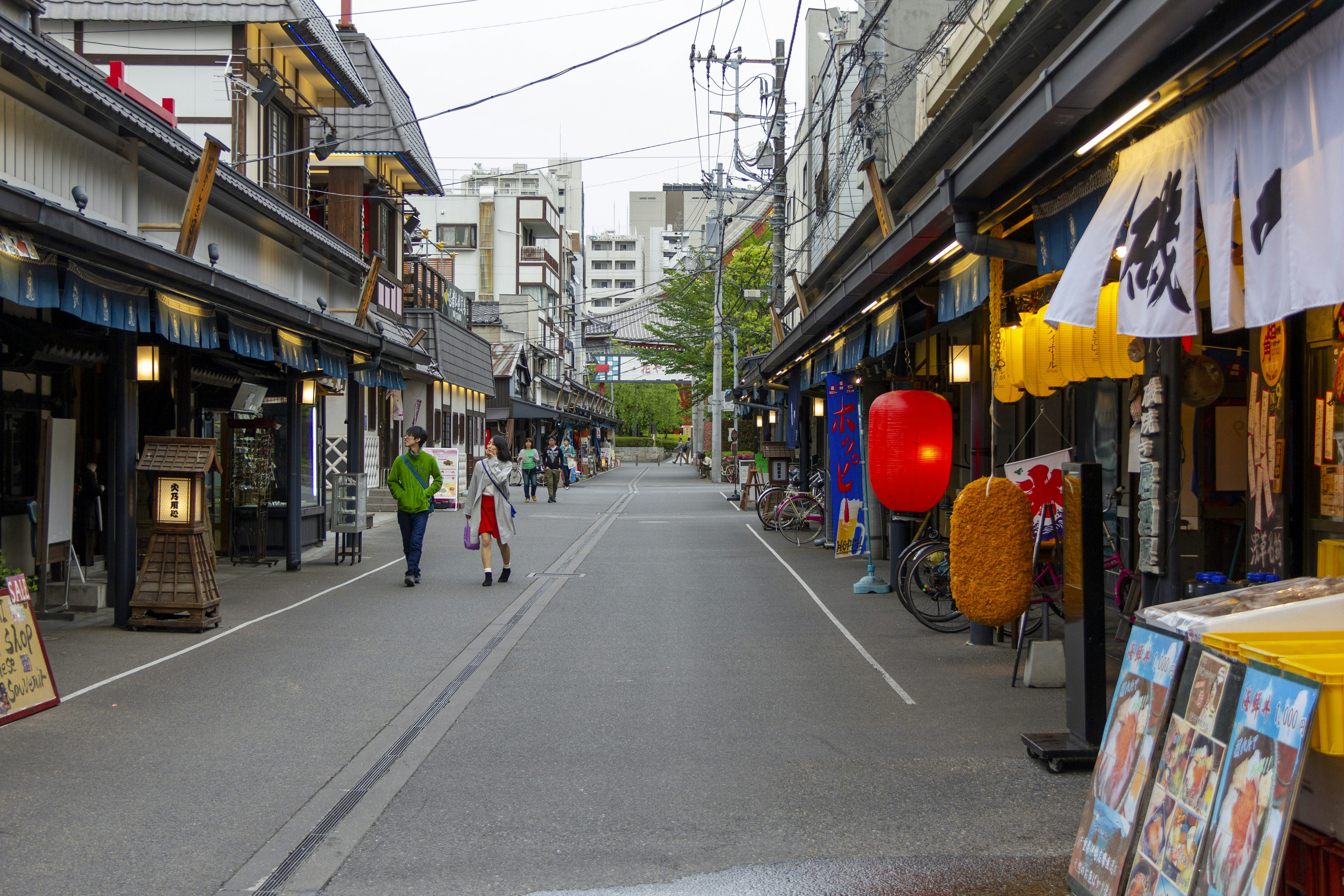 Pedestrian Pause on a Japanese Shopping Street: Lanterns, Shops, and Subtle Depth