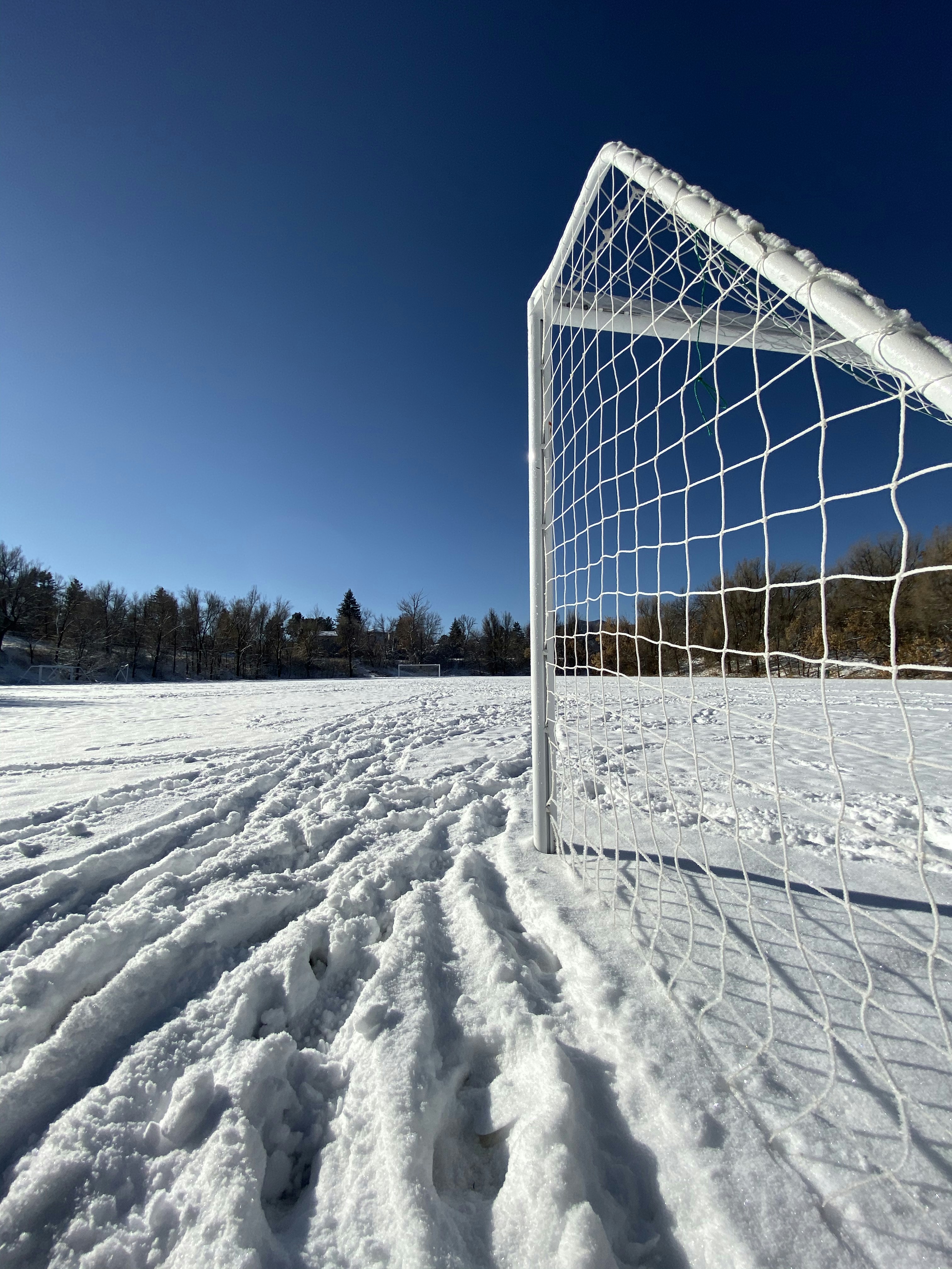 Edge of the Frame: a winter goal catching light on a snow-dusted field