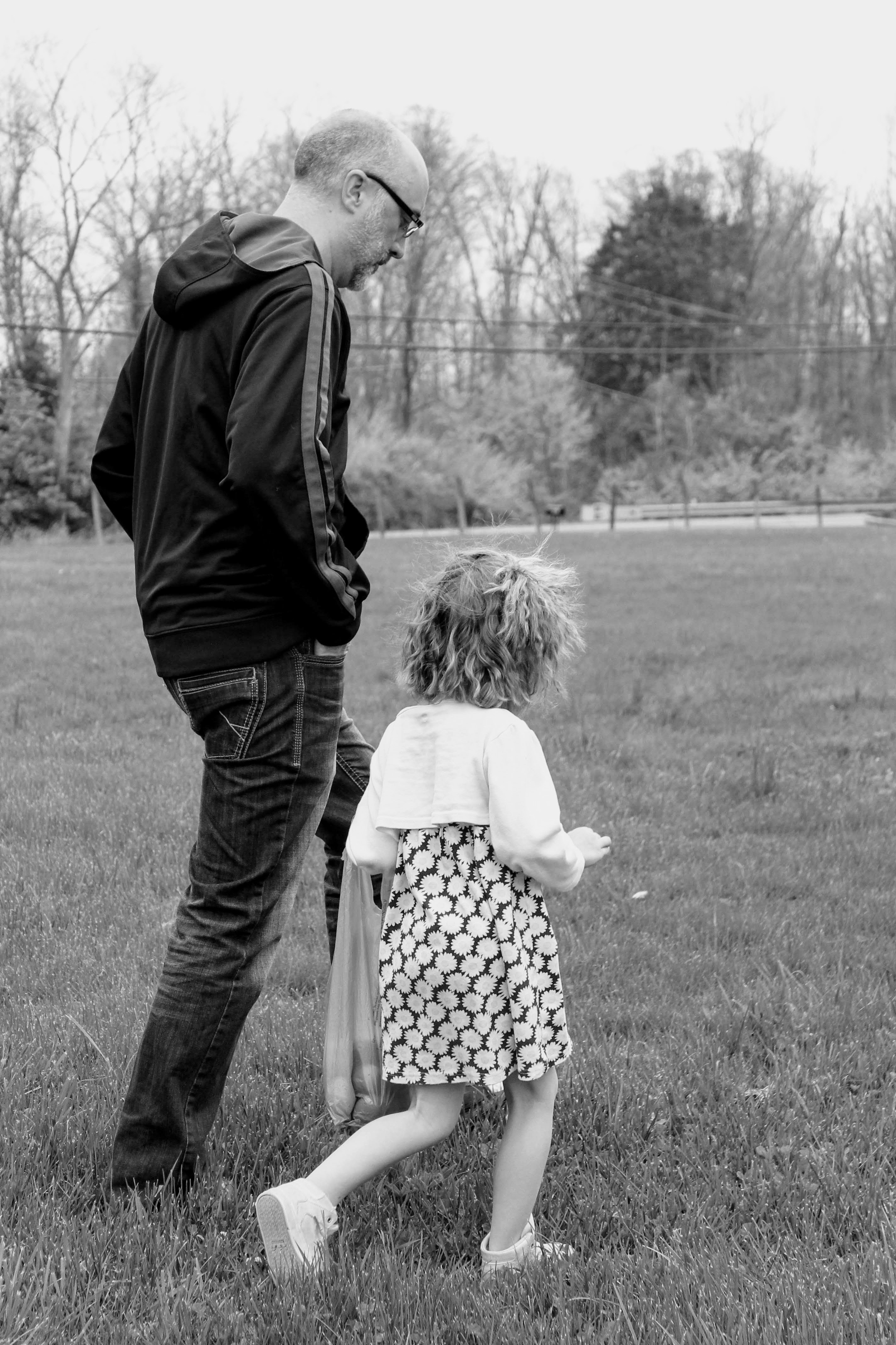 black and white photo of little girl in spring dress gathering easter eggs with father
