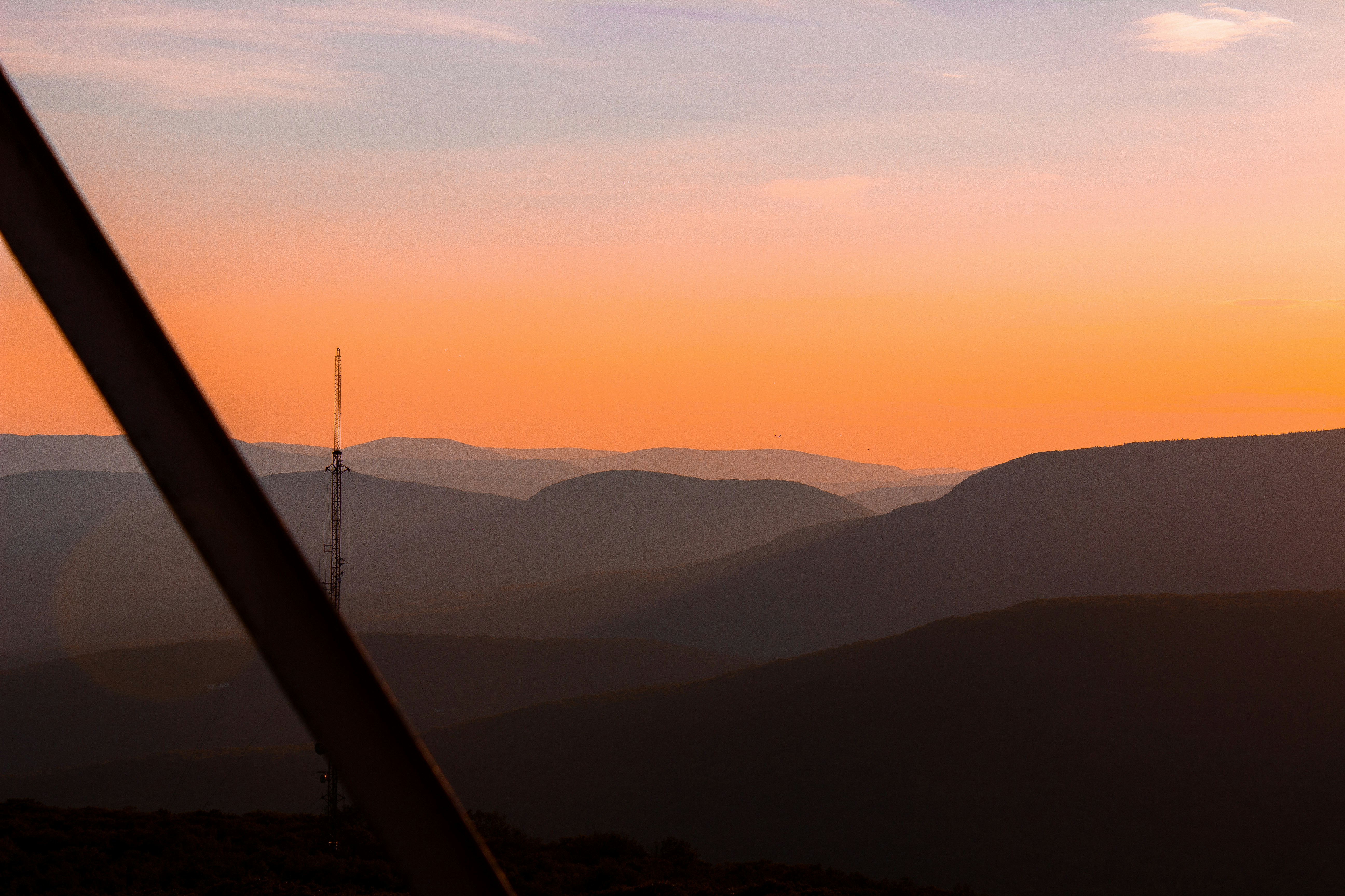 Silhouetted mountain ridges under a warm orange sunset sky.