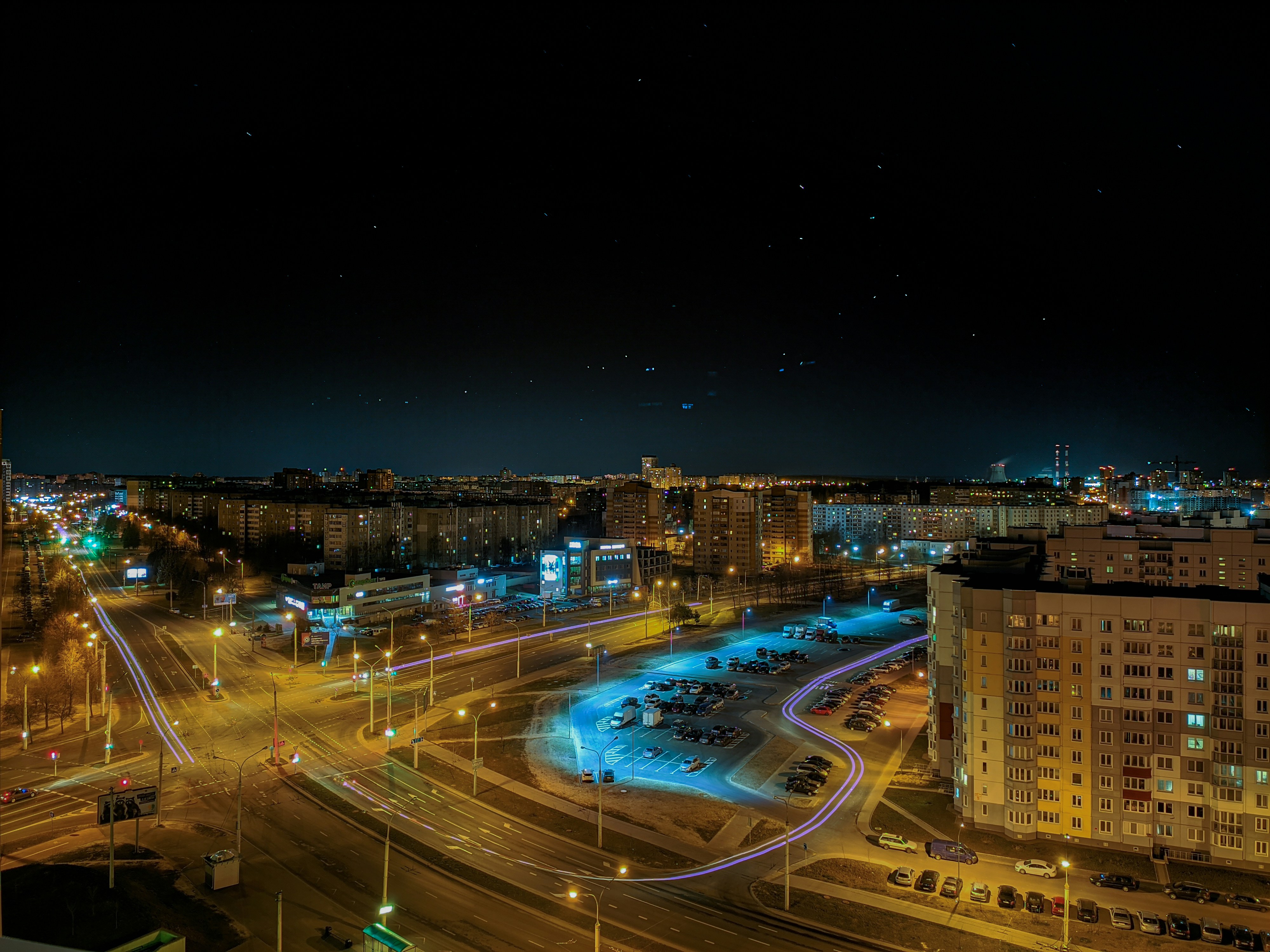 Cityscape at night with illuminated streets and a vivid night sky.