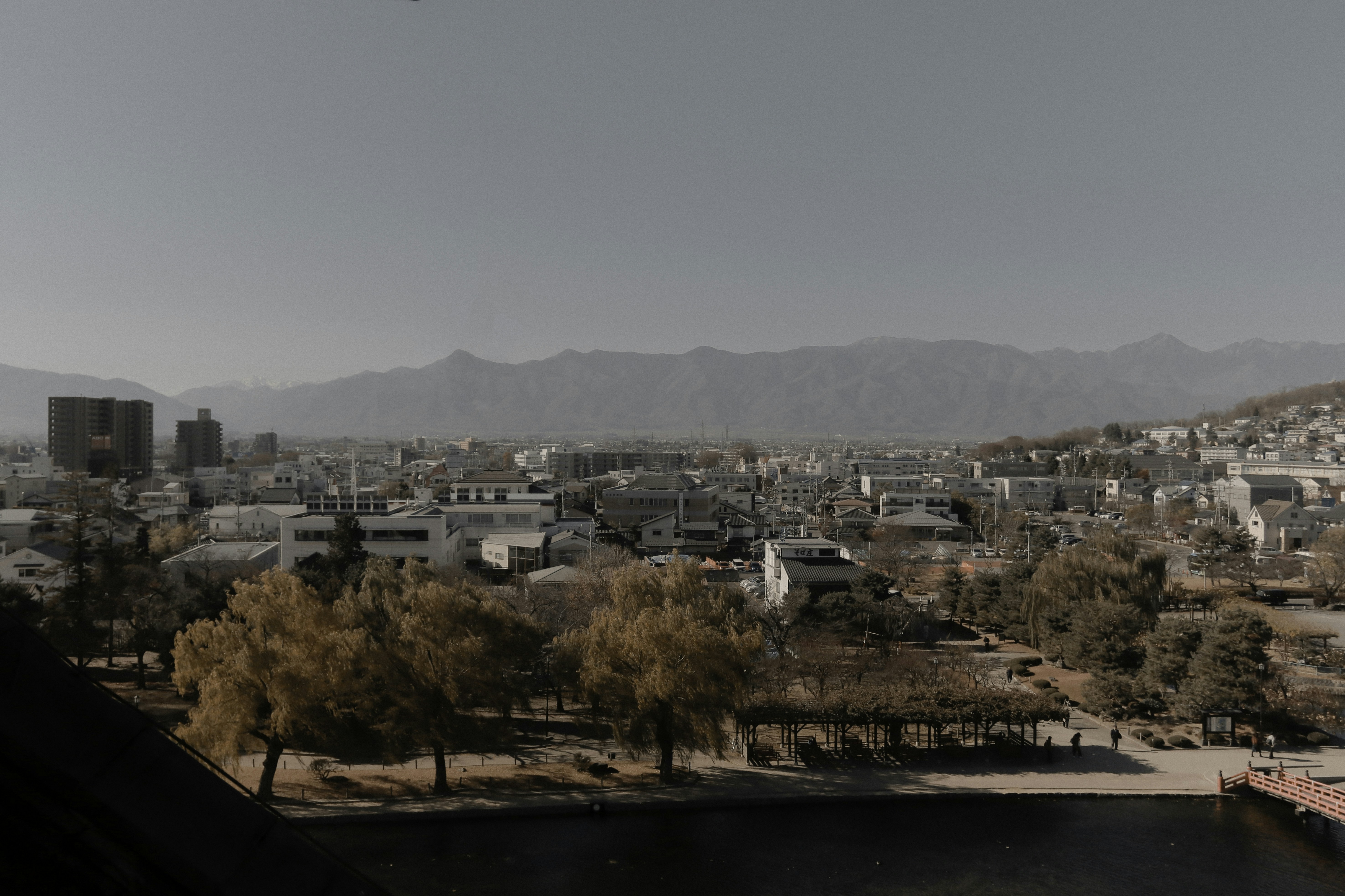 A panoramic view of a tranquil city nestled between mountains, showcasing a blend of urban structures and natural beauty.