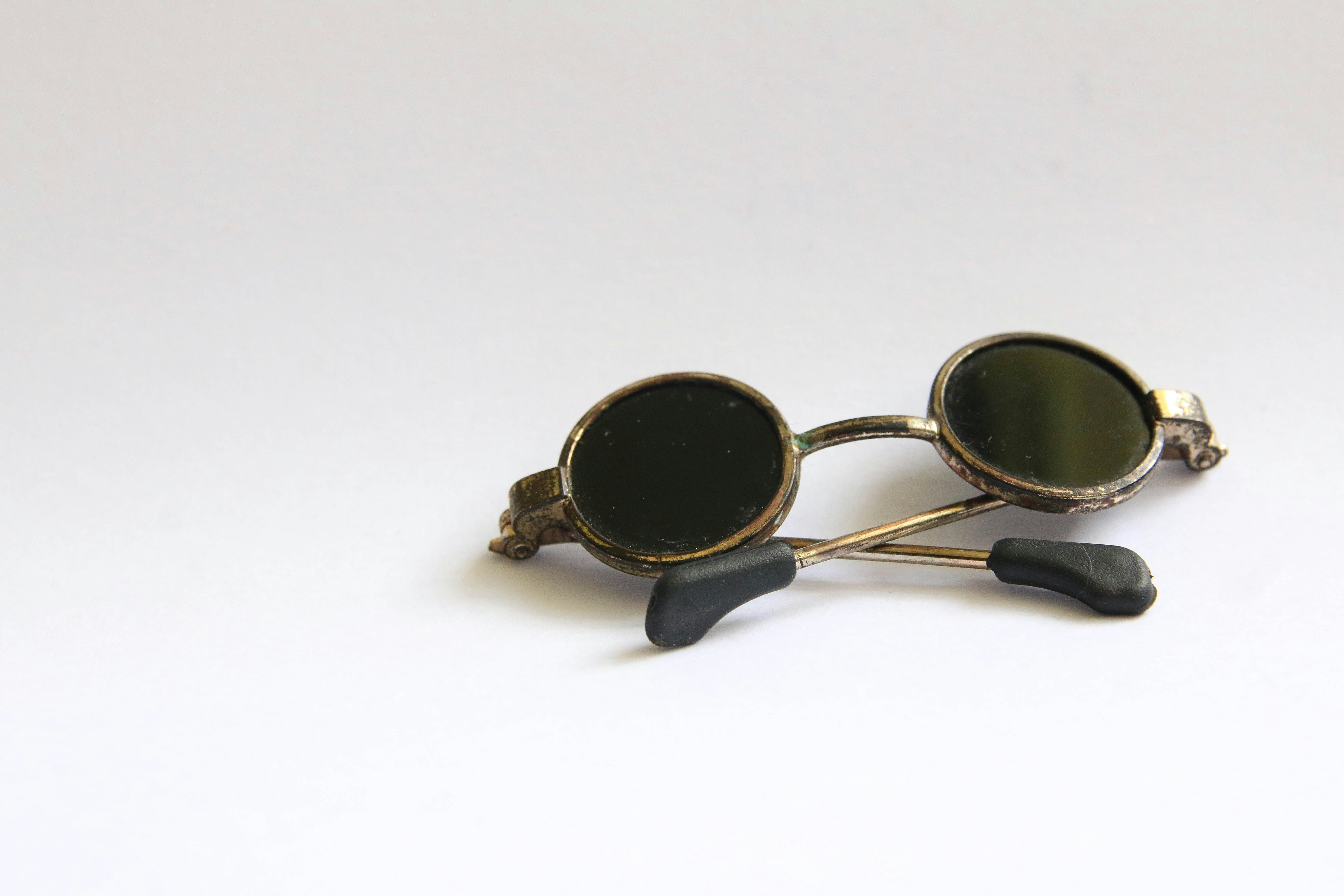 A pair of vintage sunglasses resting on a smooth surface, showcasing their worn yet charming design. The reflective lenses hint at stories untold.