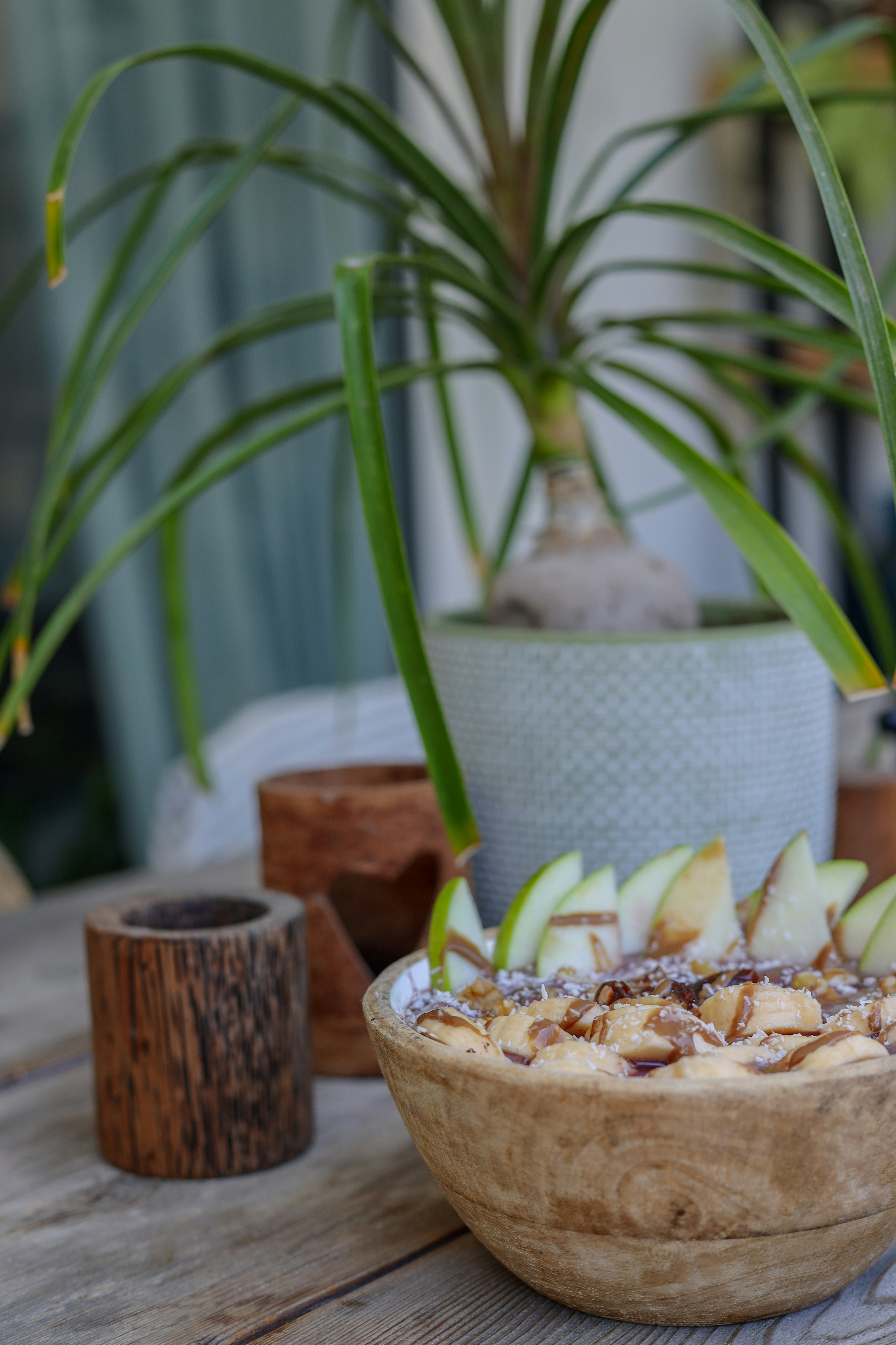 Crunch and Calm: A Wooden Bowl of Pears and Apples Framed by a Leafy Plant