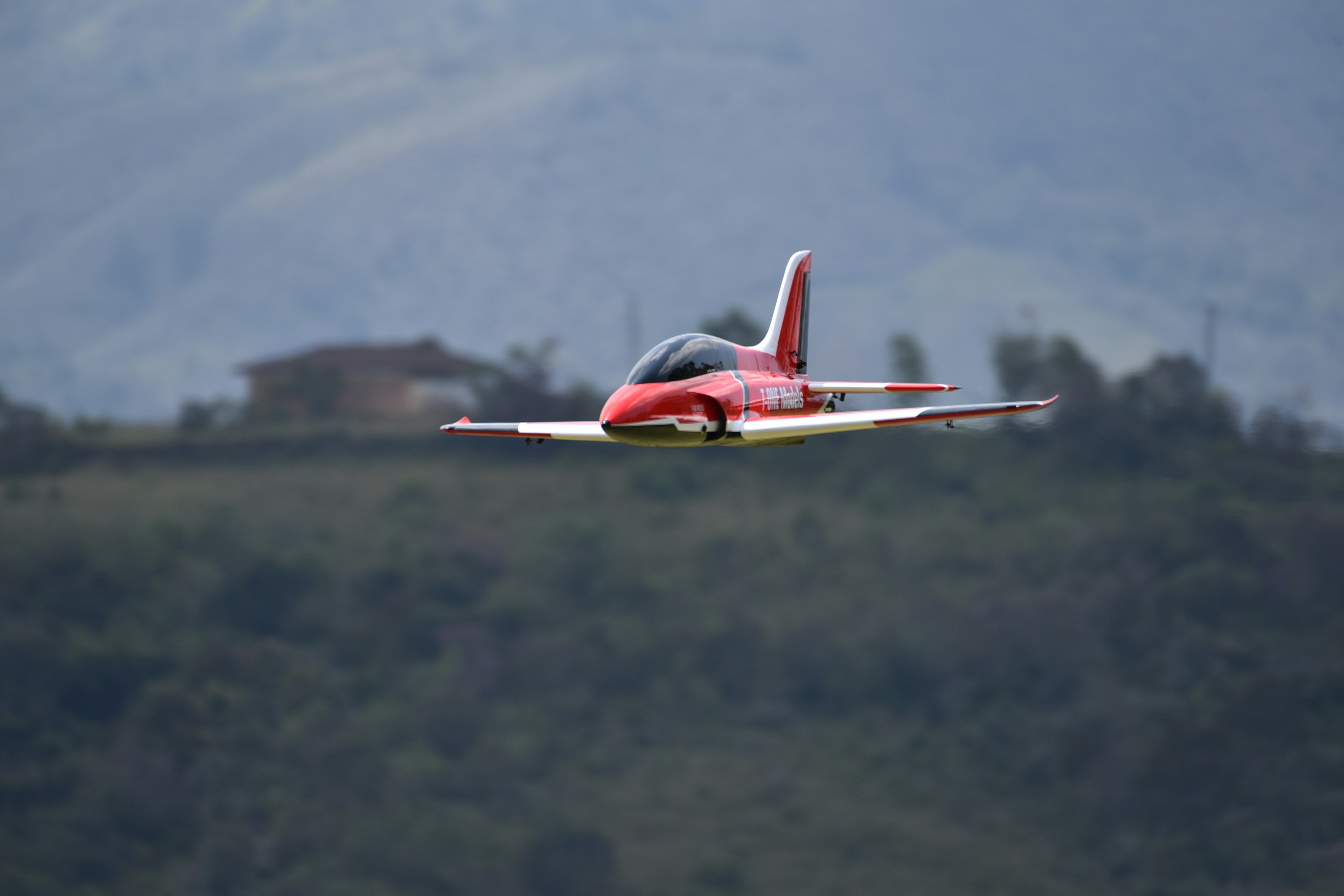 Red and white airplane flying over green mountains during daytime photo ...