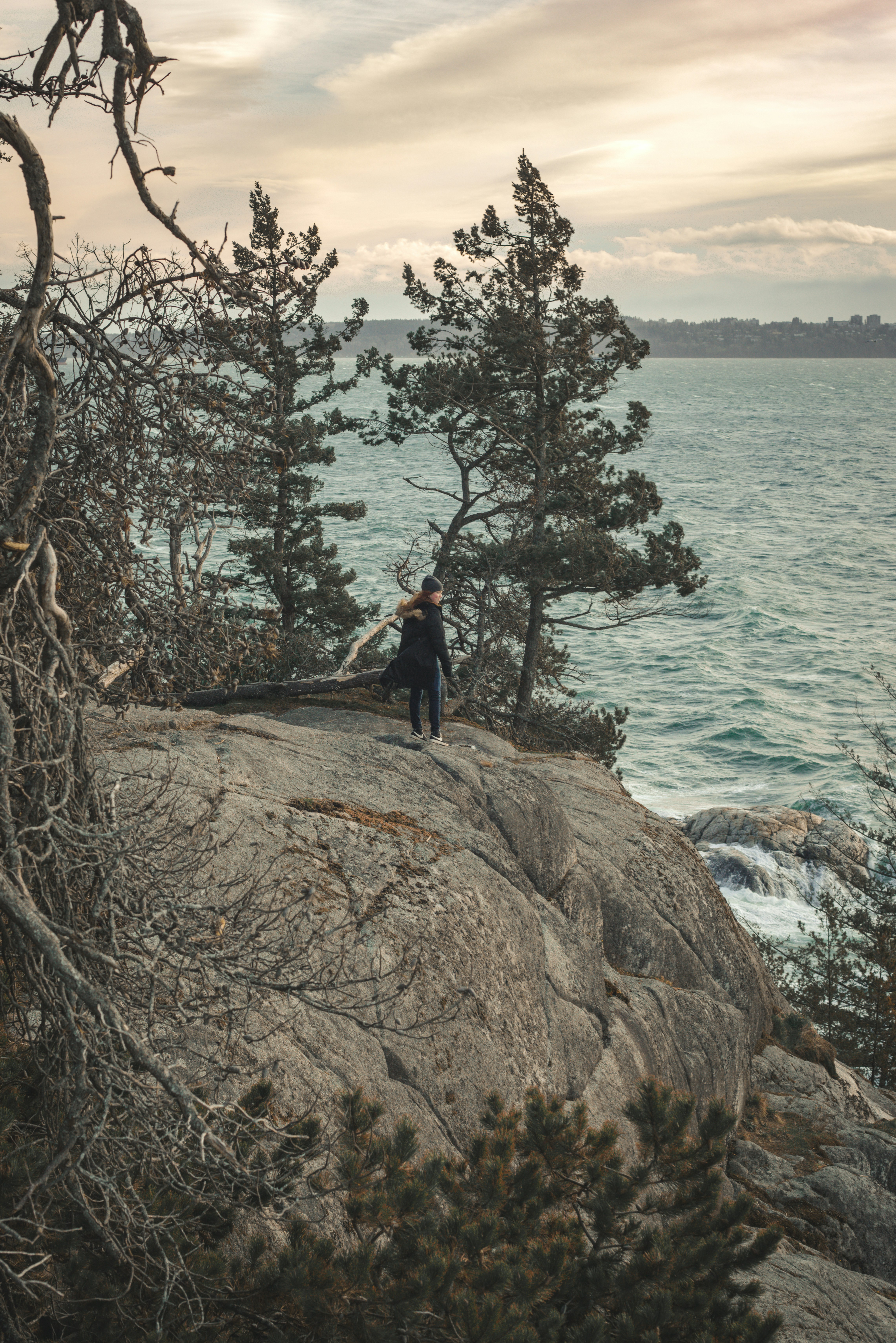 Ridge Above the Sea: A lone figure on weathered rock looking toward the horizon