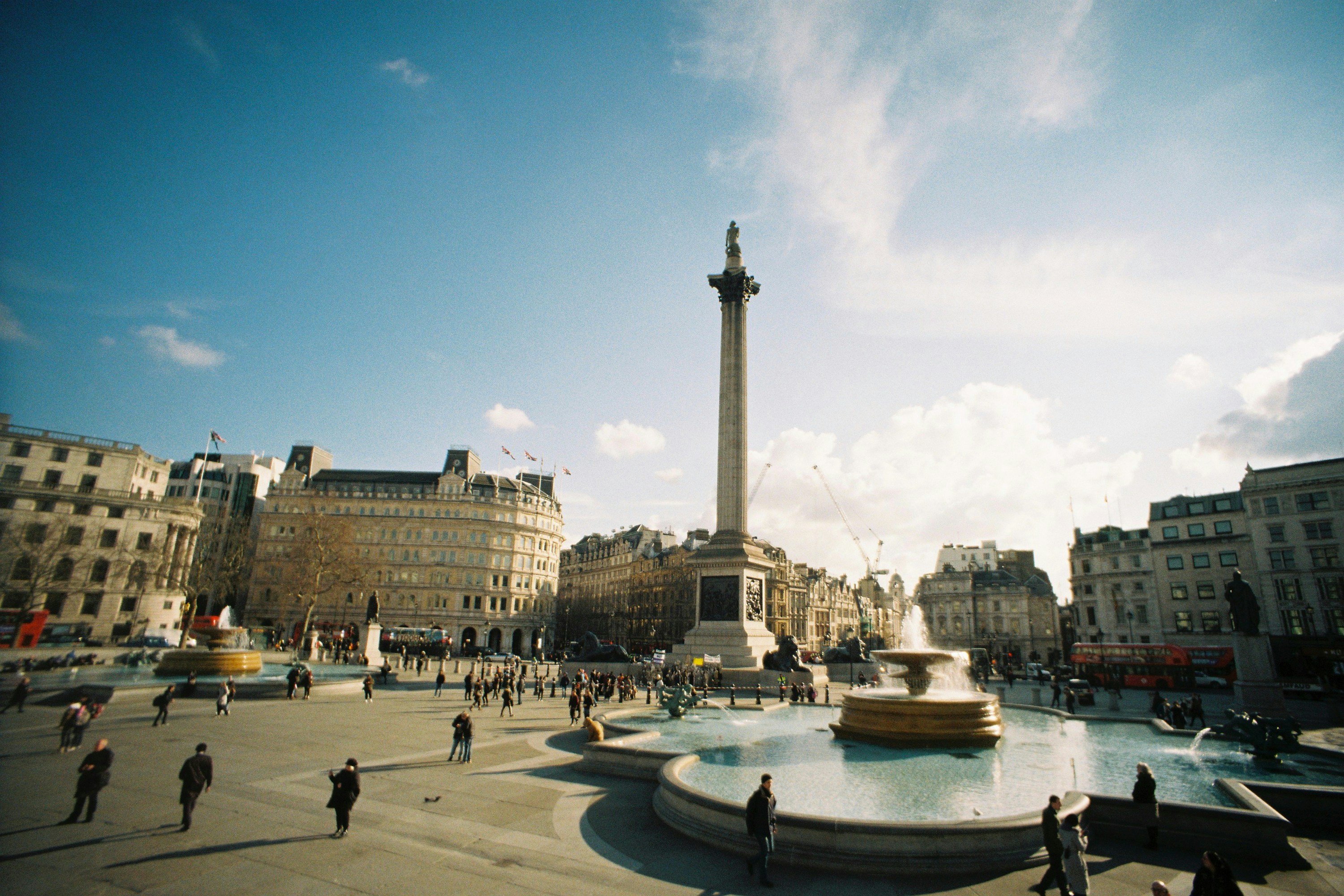 Wide angle view of tourists walking around Trafalgar Square and Nelson's Column in London. Shot on film.