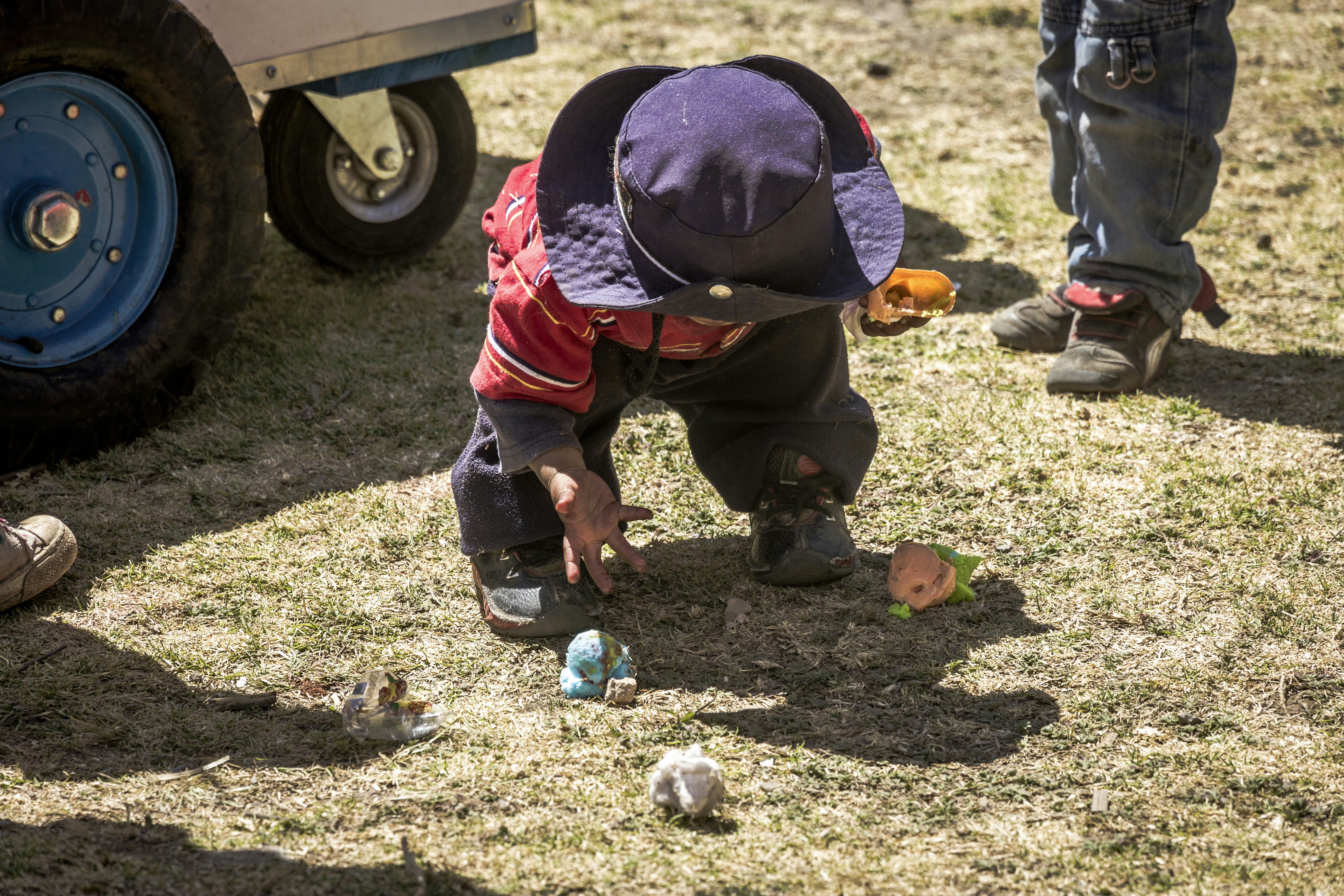 Mini Explorer Gathering Colorful Pebbles Under Sunlit Ground