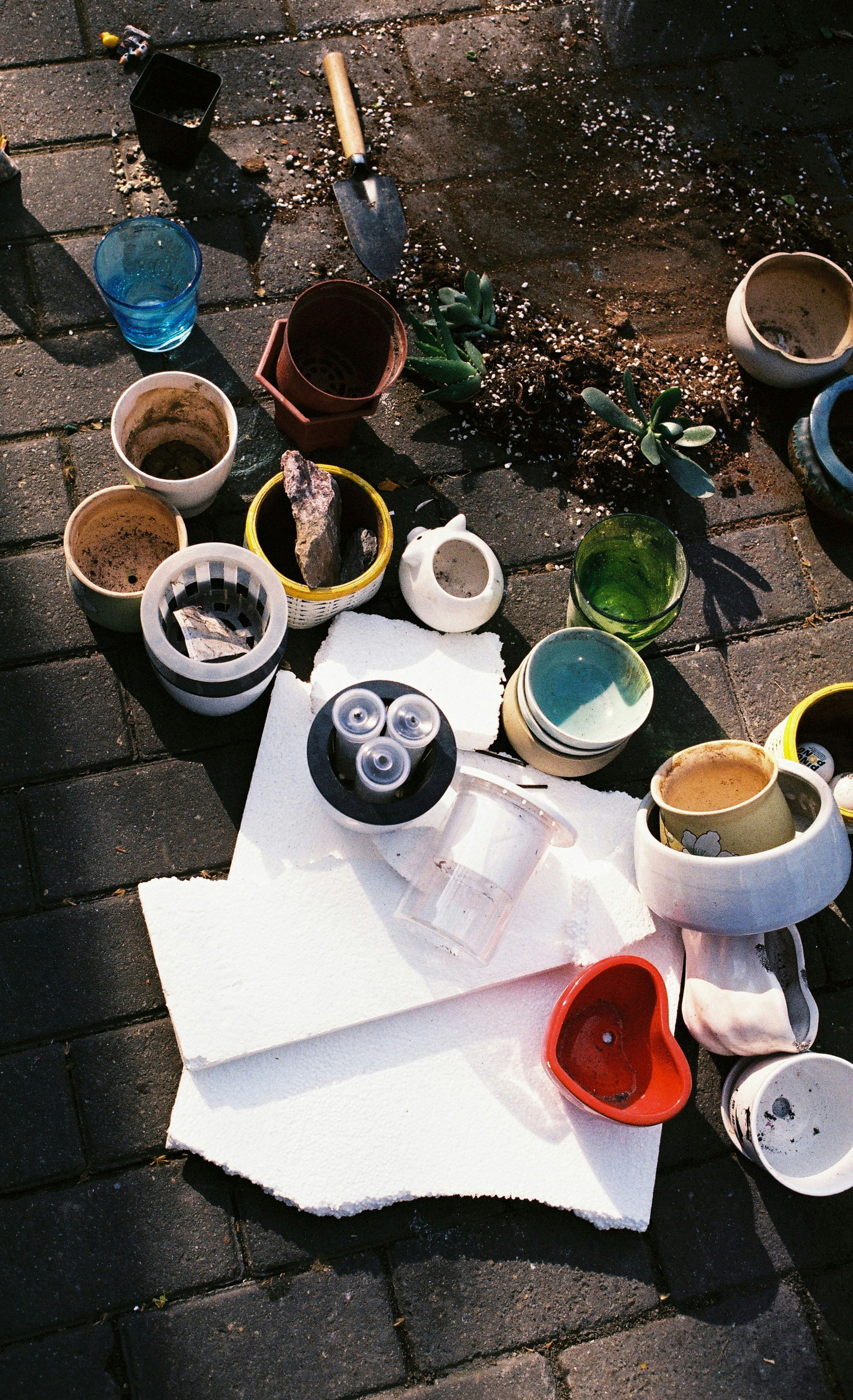 Colorful array of empty plant pots scattered on a stone surface, accompanied by gardening tools and soil. A glimpse into the vibrant world of gardening.