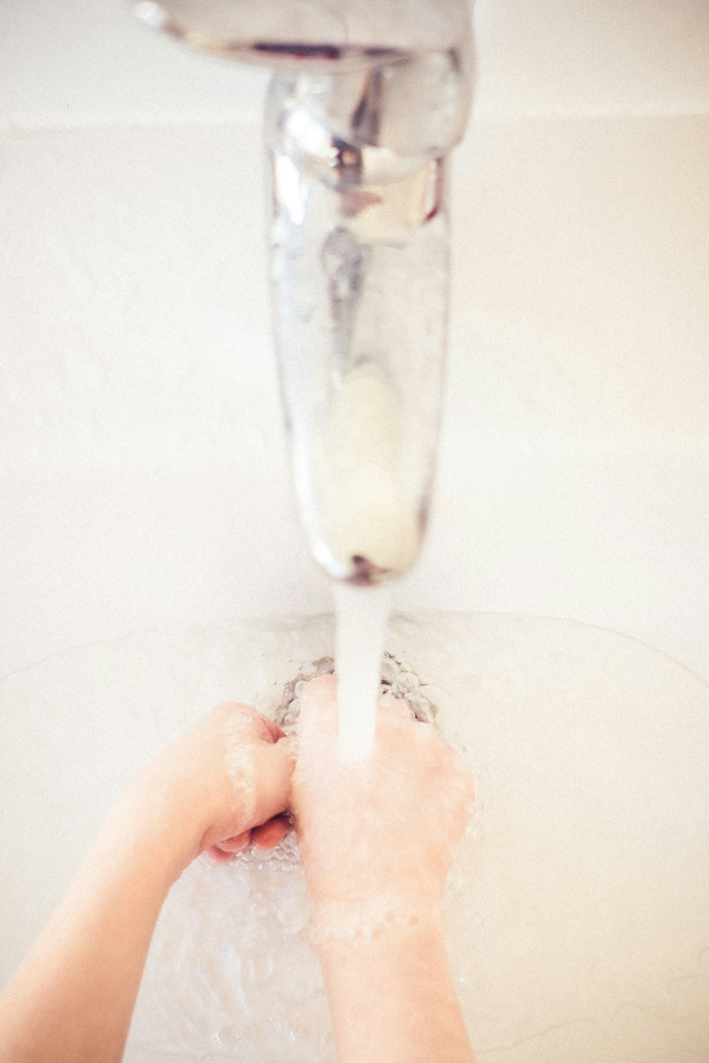 Hands submerged in water beneath a shining faucet, capturing the essence of daily rituals and cleanliness.