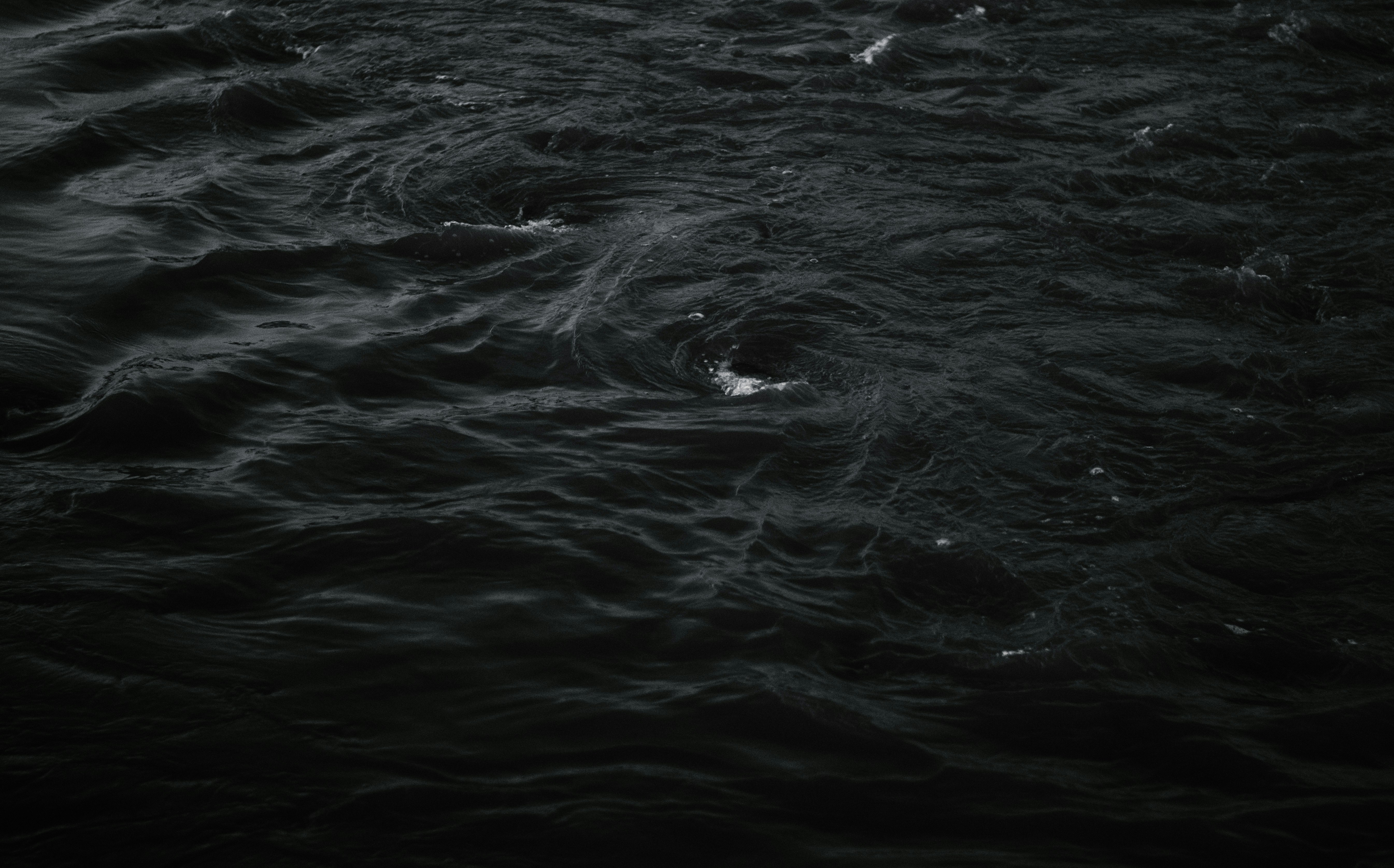 Dark, swirling water surface reflecting subtle light patterns, creating an enigmatic atmosphere.