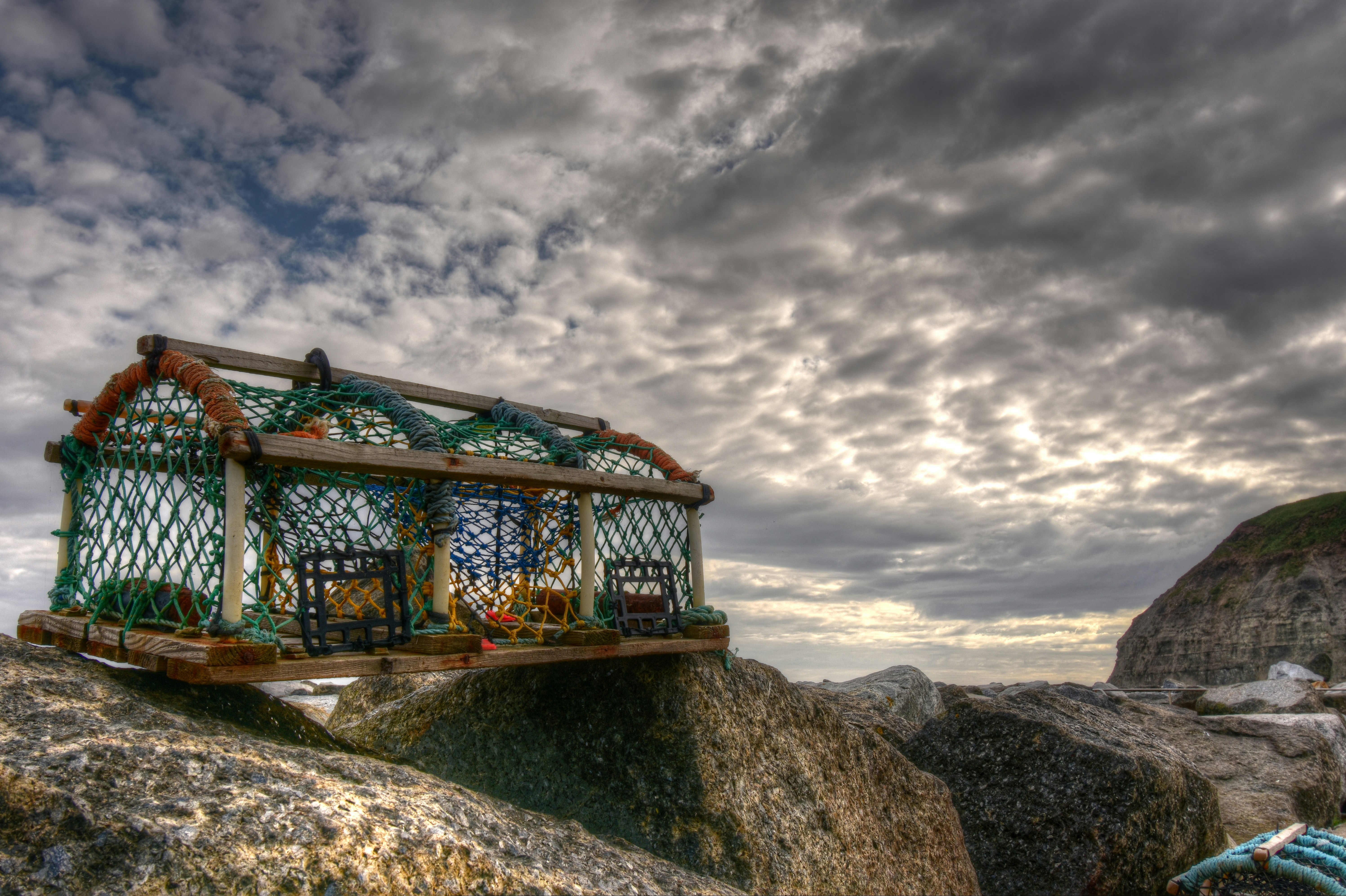 Seascape Cage: Cliffside Lobster Trap Adrift on sunlit rocks