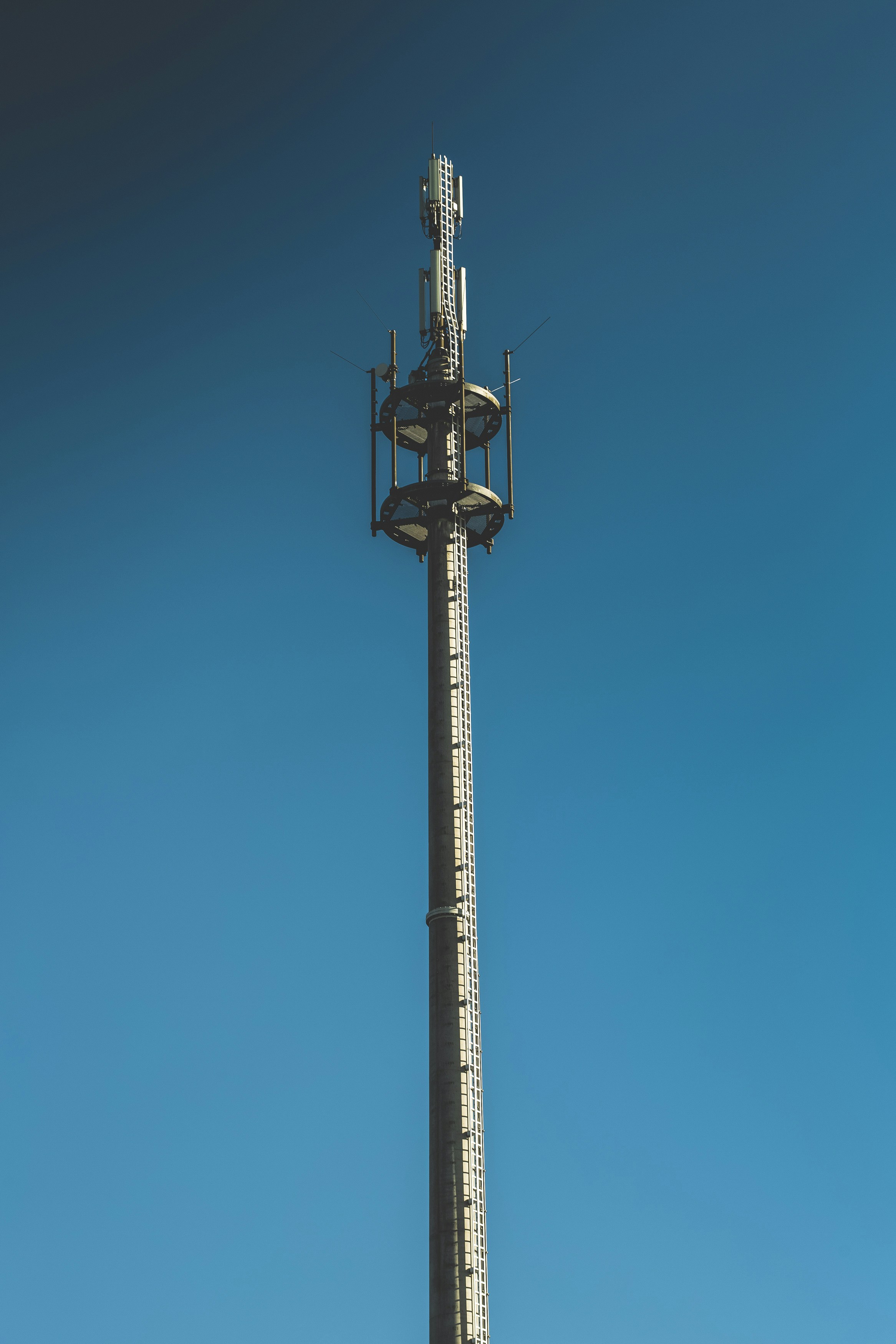 Telecommunication tower reaching into a clear blue sky, symbolizing modern connectivity and infrastructure.
