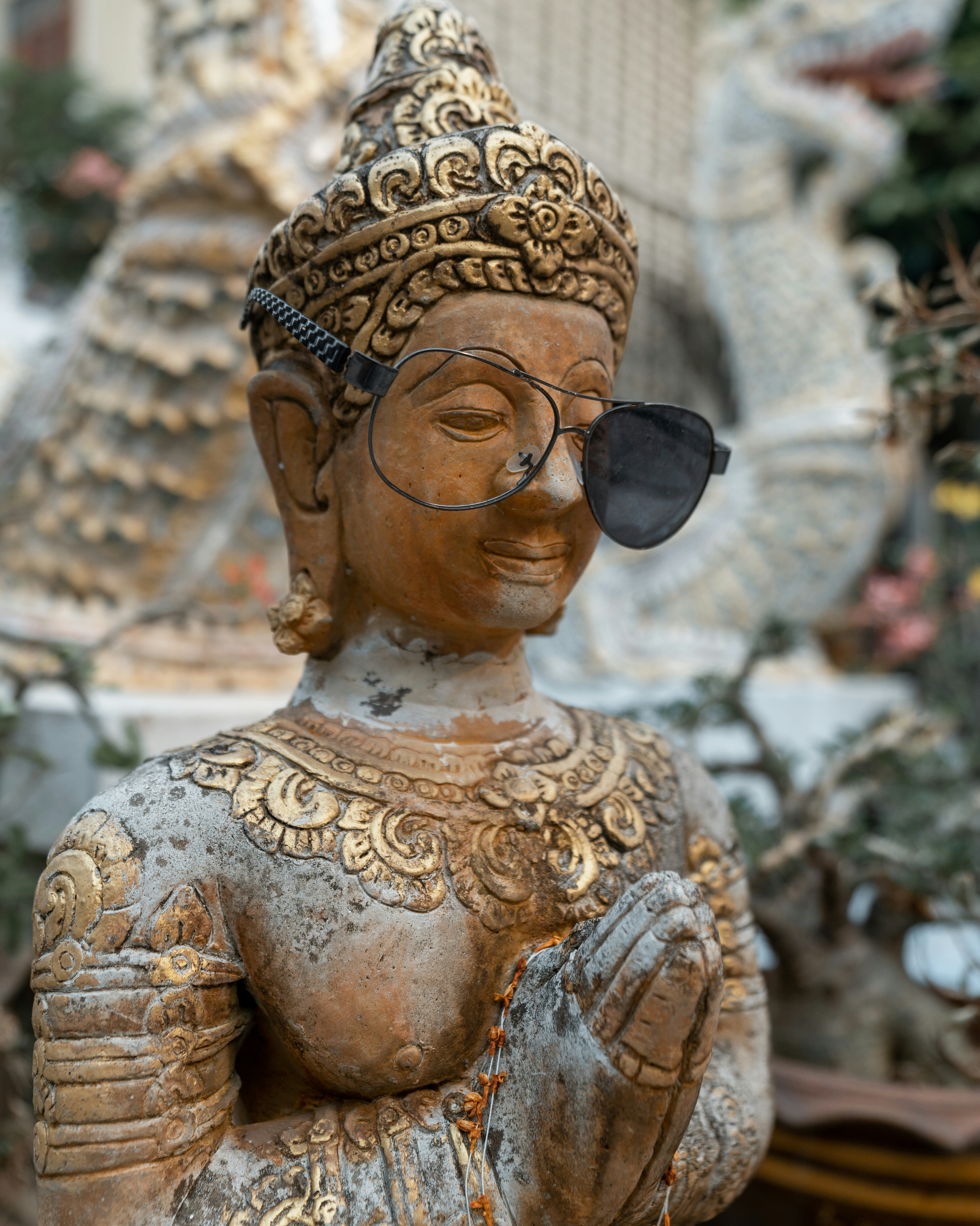 Sunglasses-Wearing Buddha: Quiet Charm Amid Ornate Stone Carvings