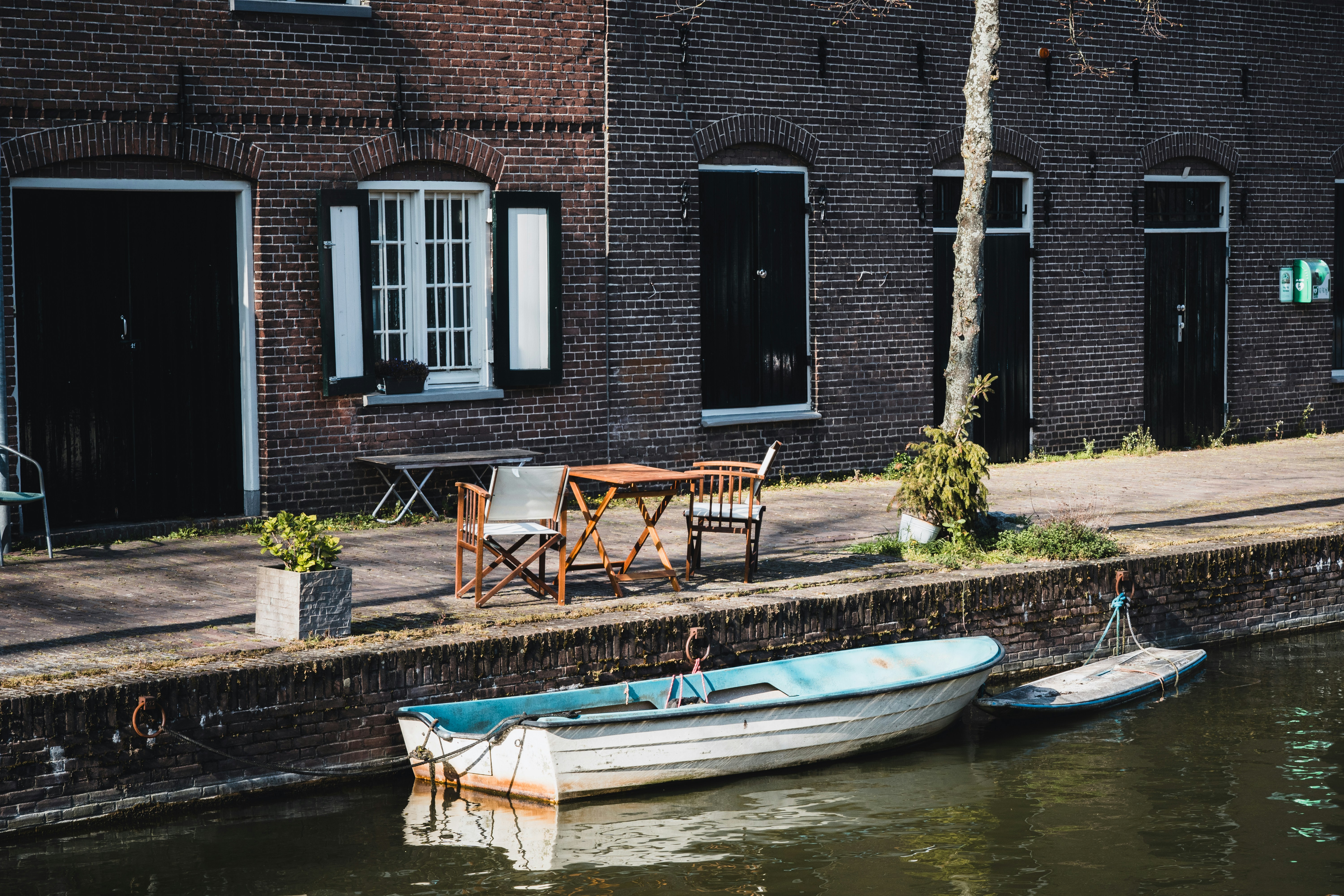 Canal-side Calm: A Brick Courtyard, Two Boats, and an Empty Table