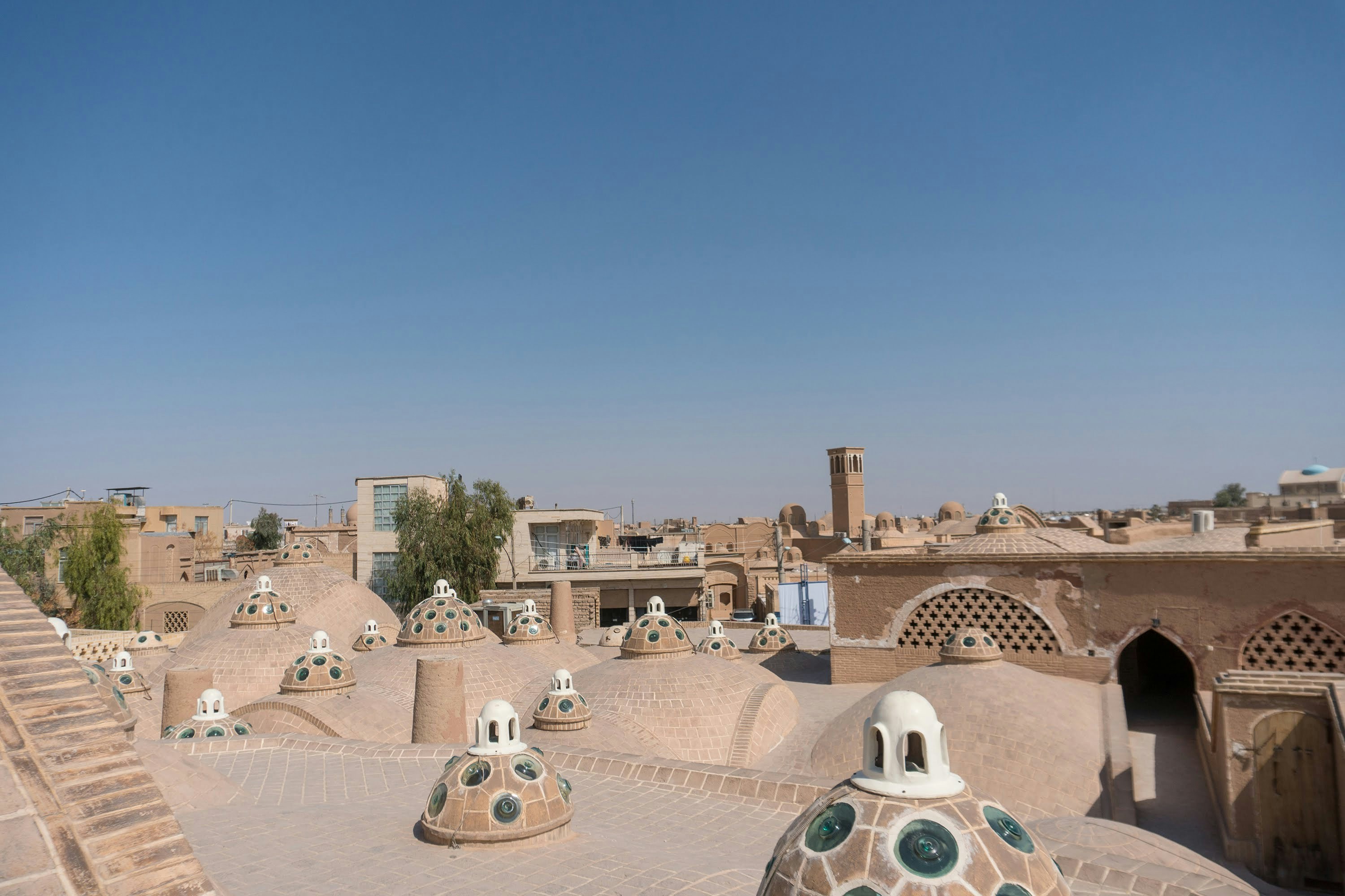 Traditional domed rooftops of an ancient cityscape under a bright blue sky.