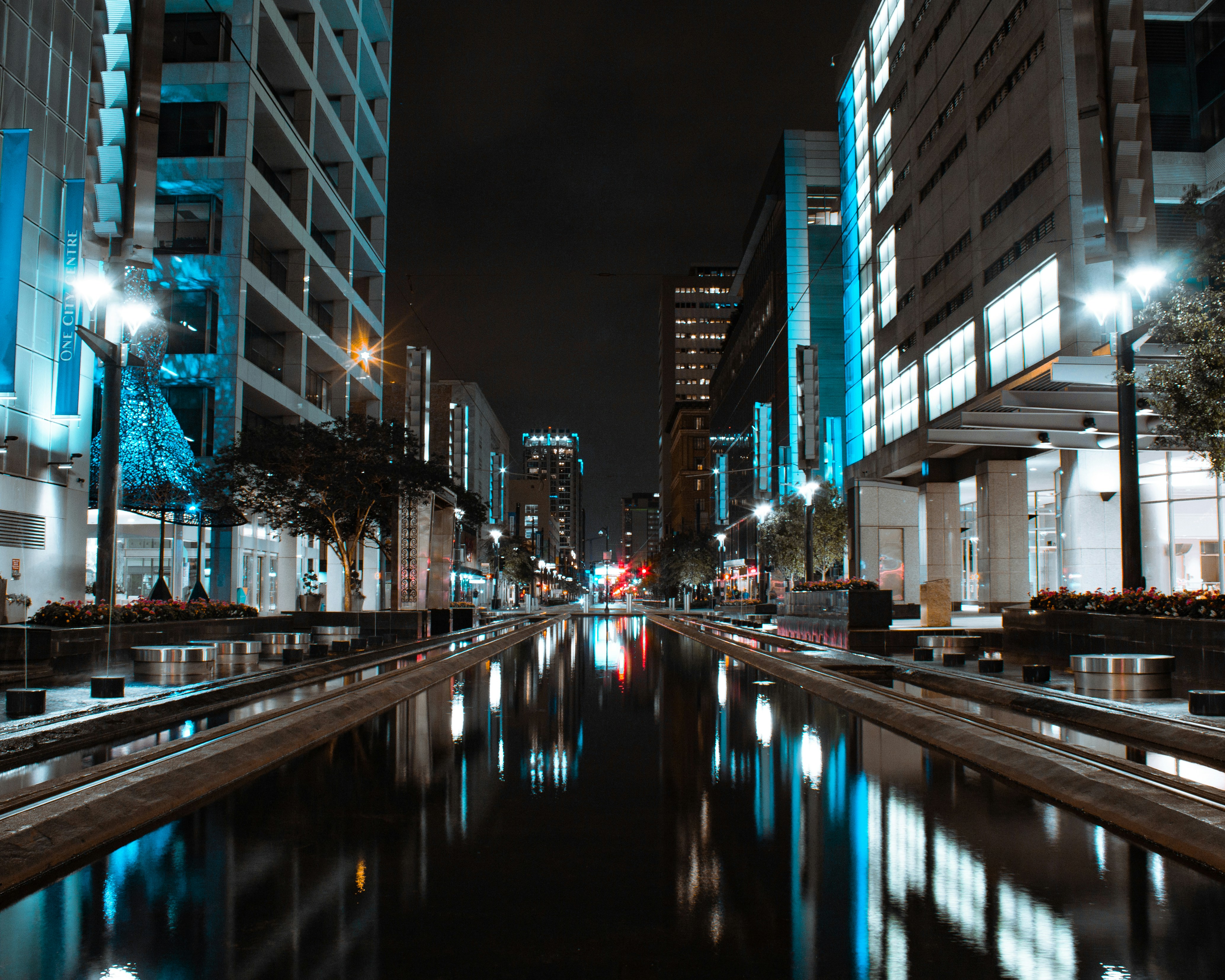 Cityscape with illuminated buildings reflecting on a canal at night.