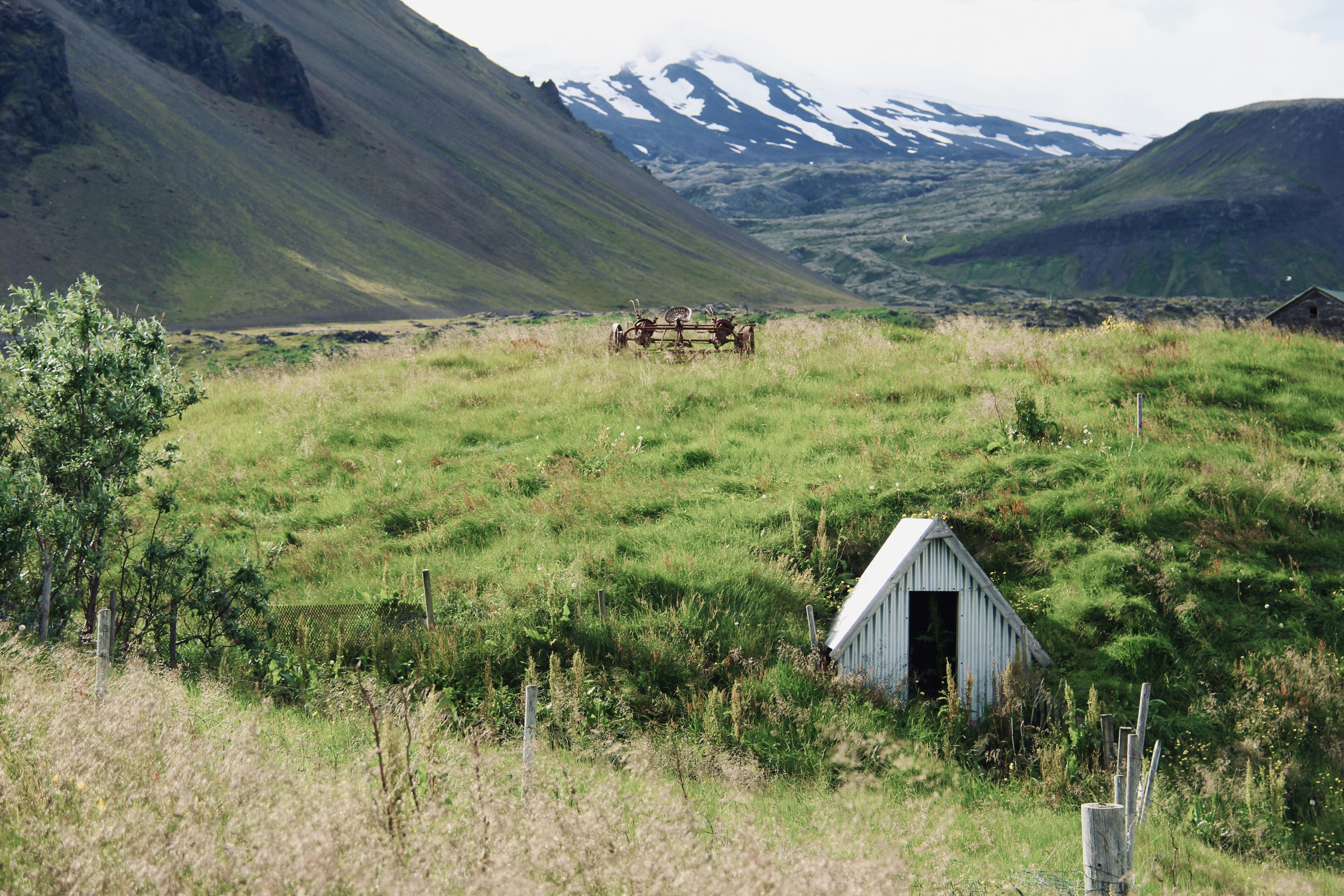 white wooden house on green grass field near mountain during daytime