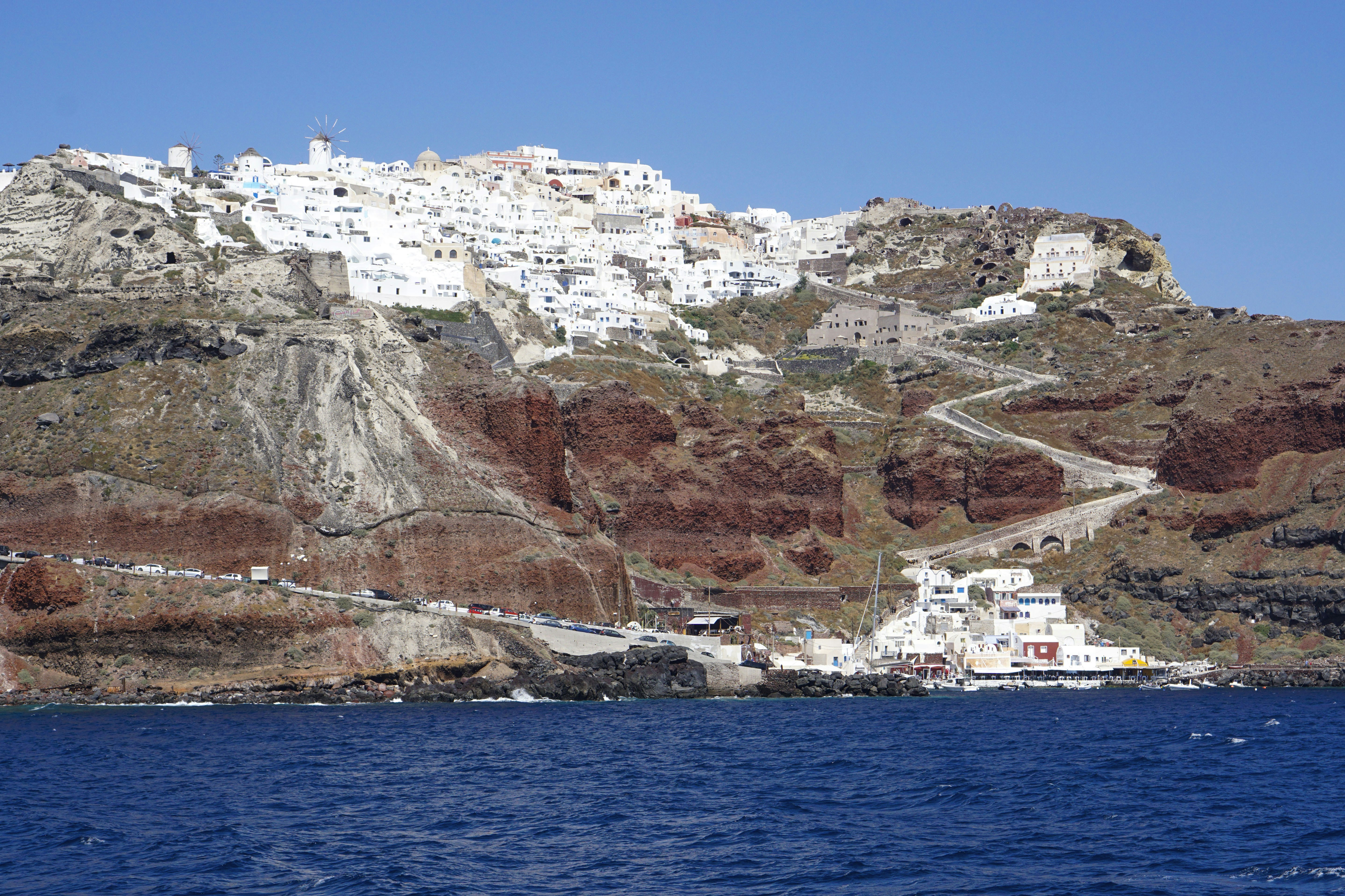 White buildings perched on a cliffside overlooking the deep blue sea, showcasing the unique architecture of Santorini.