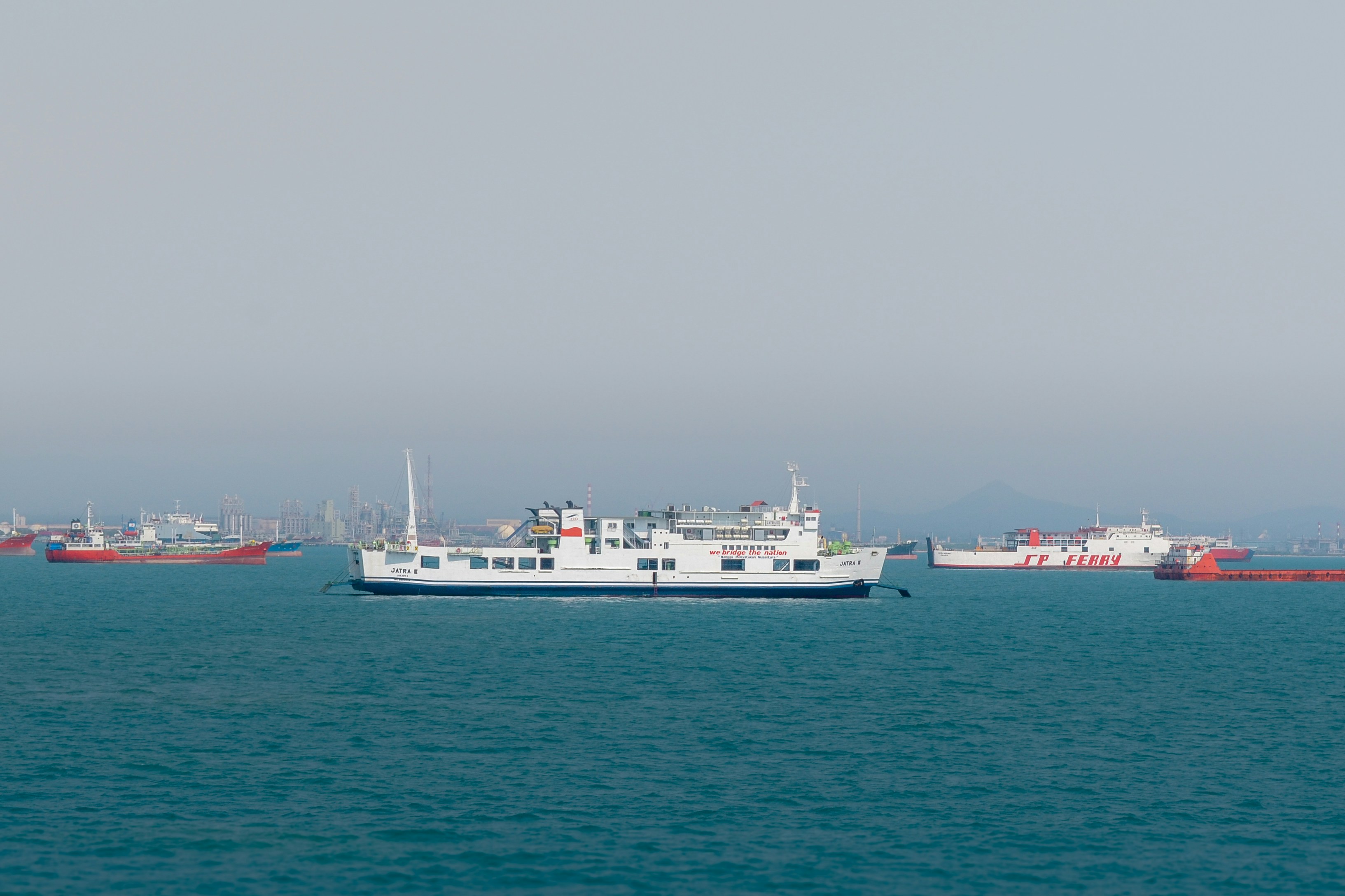 Ferry navigating through foggy waters at Merak Sea Port with distant ships visible.