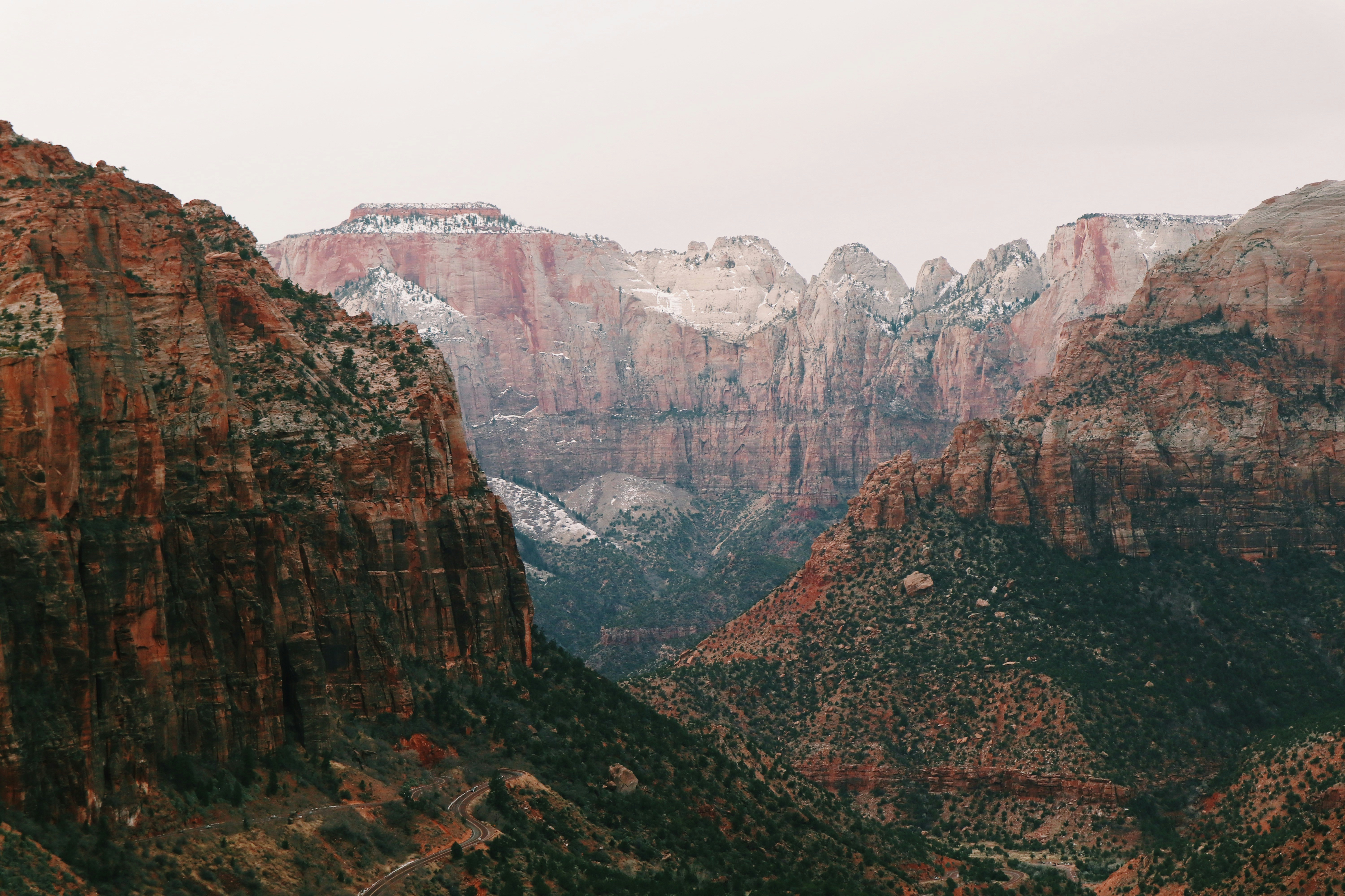 Expansive view of rugged brown and red mountains under an overcast sky.