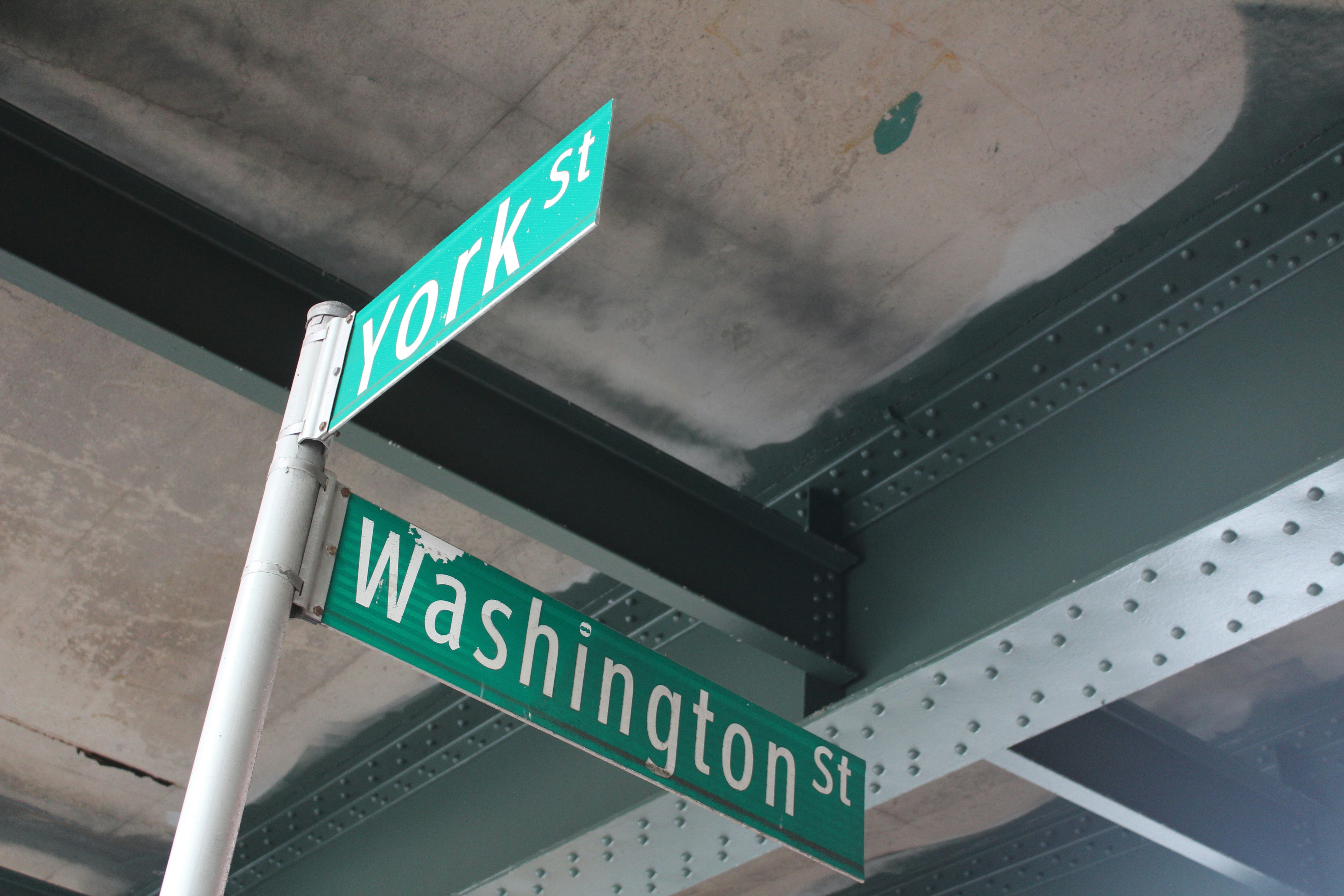 Crossroads Under Steel: Street Sign Angles at a Rooftop Junction
