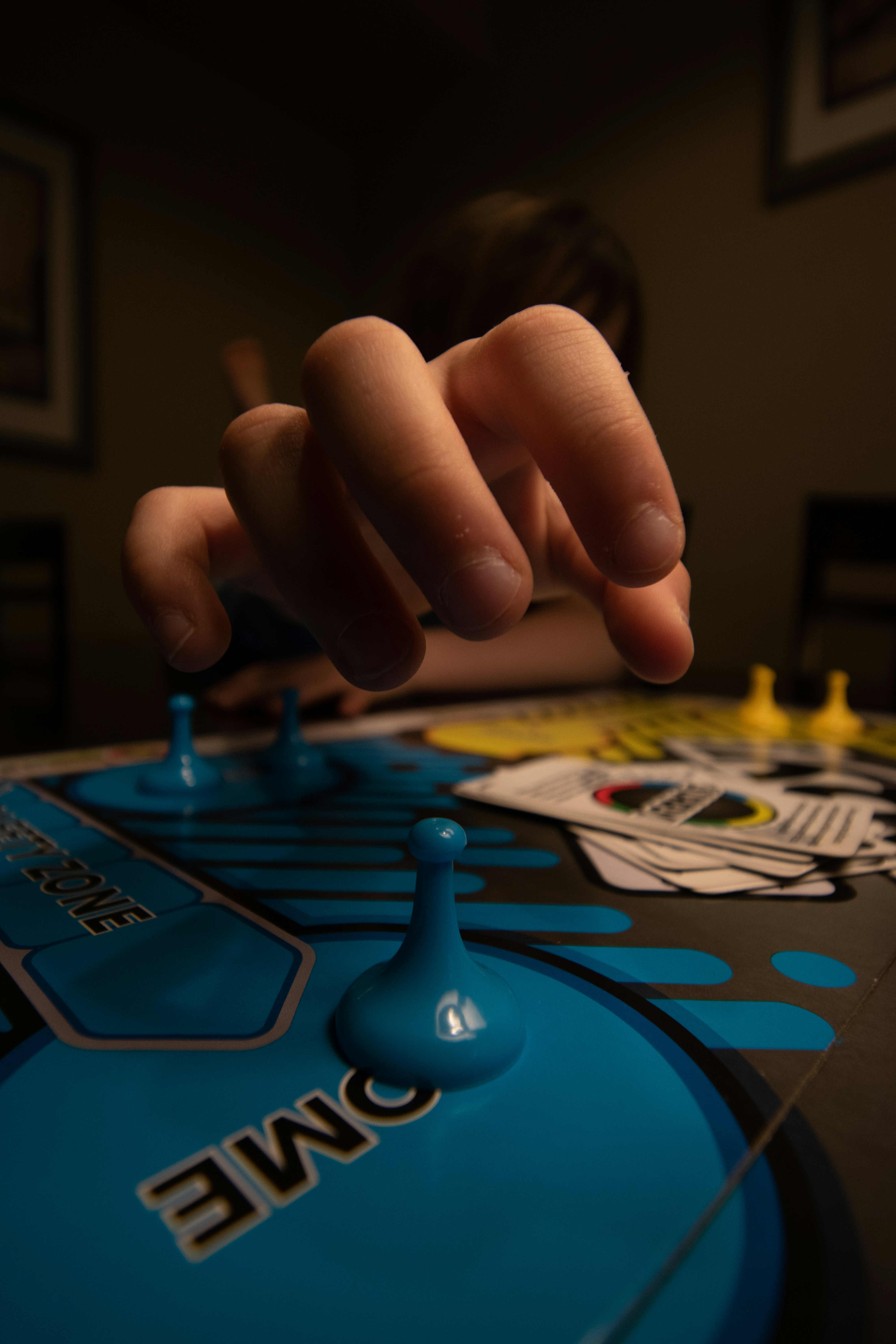 Blue Pawn in Focus as a Hand Reaches Across the Game Board