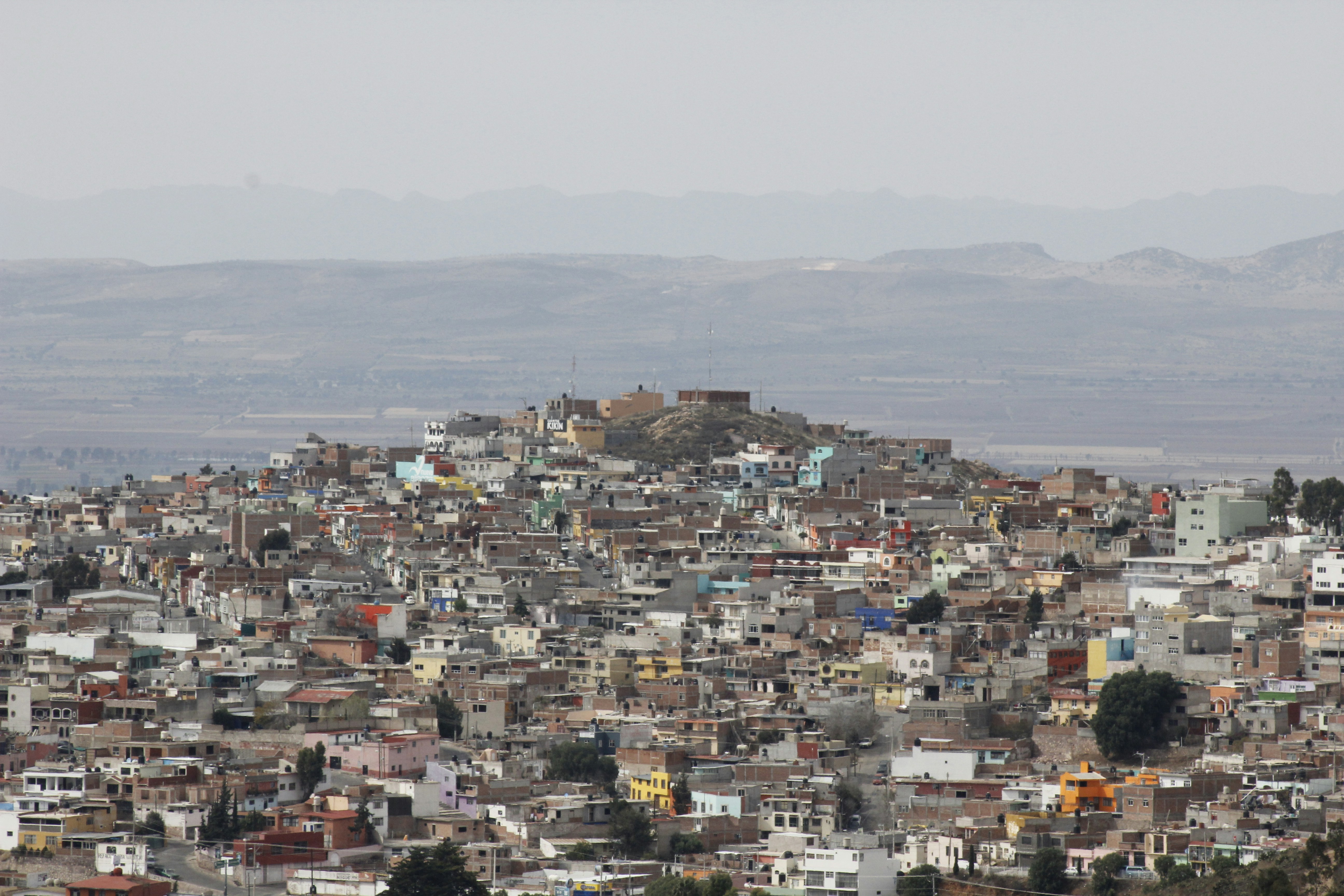 Expansive cityscape sprawling over a hill with distant desert landscape in the background.