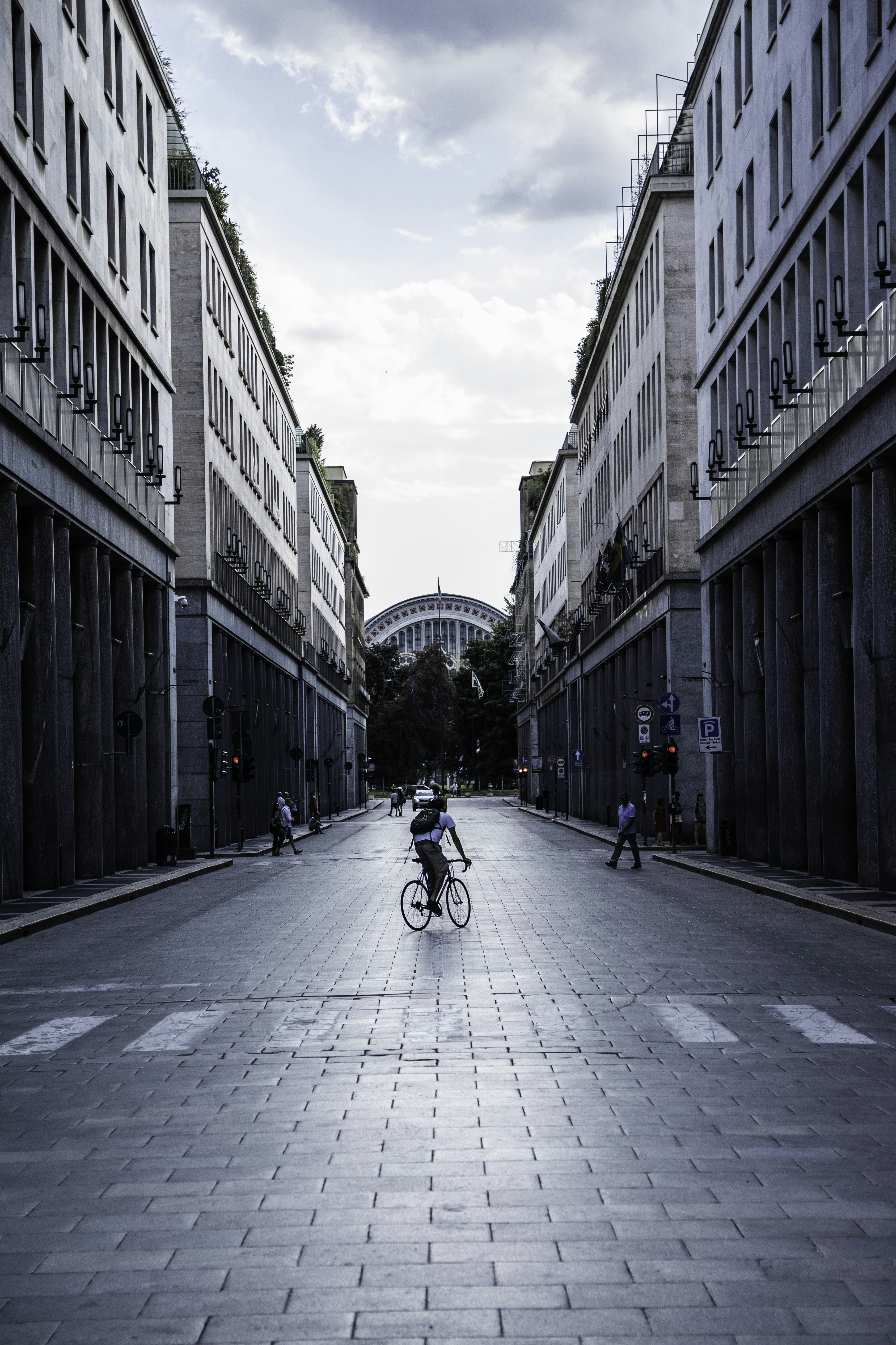 Man in black jacket riding bicycle on road between high rise buildings ...