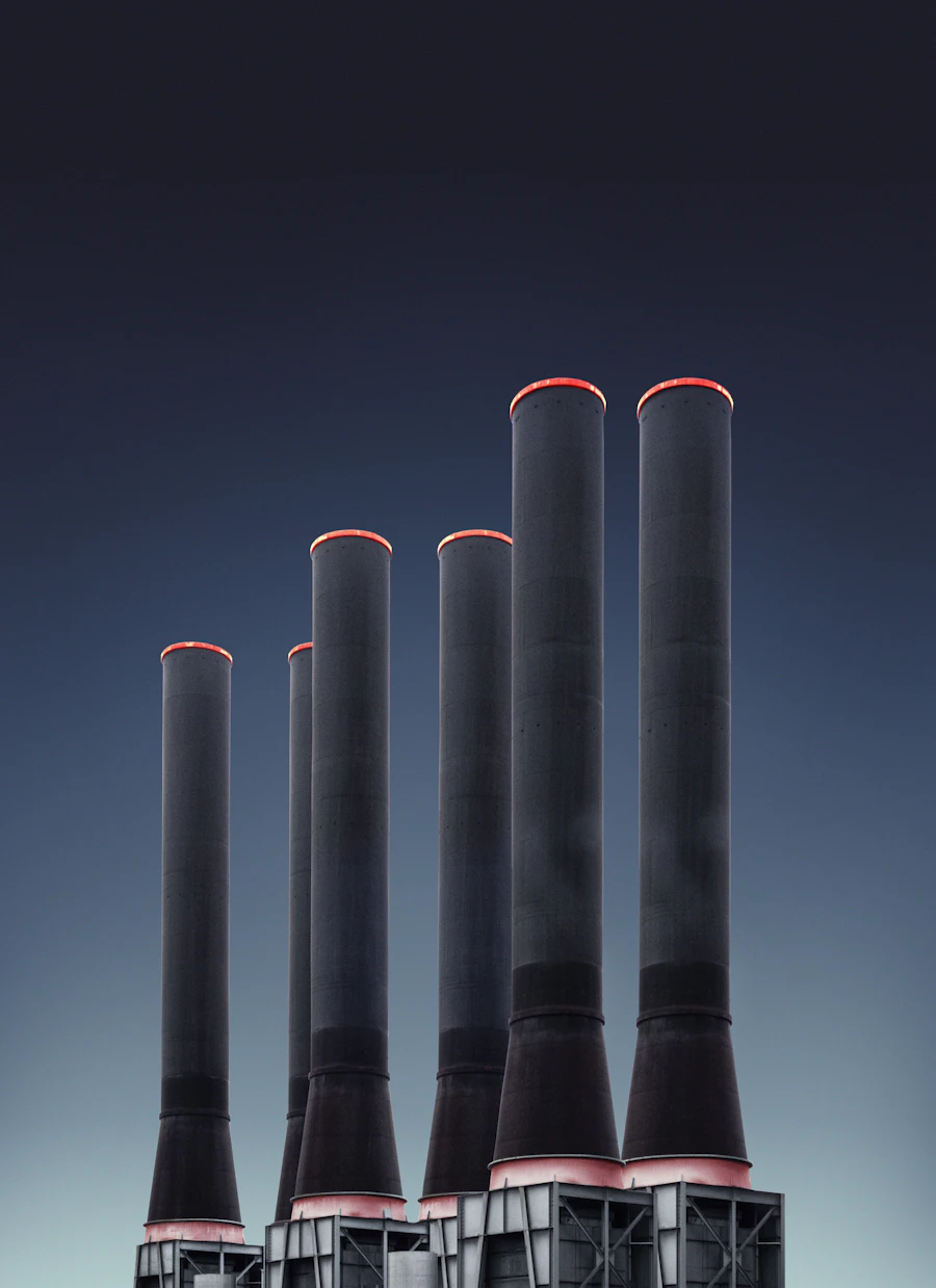 A series of tall industrial smokestacks rise against a gradient dark sky, showcasing their imposing structure and design.